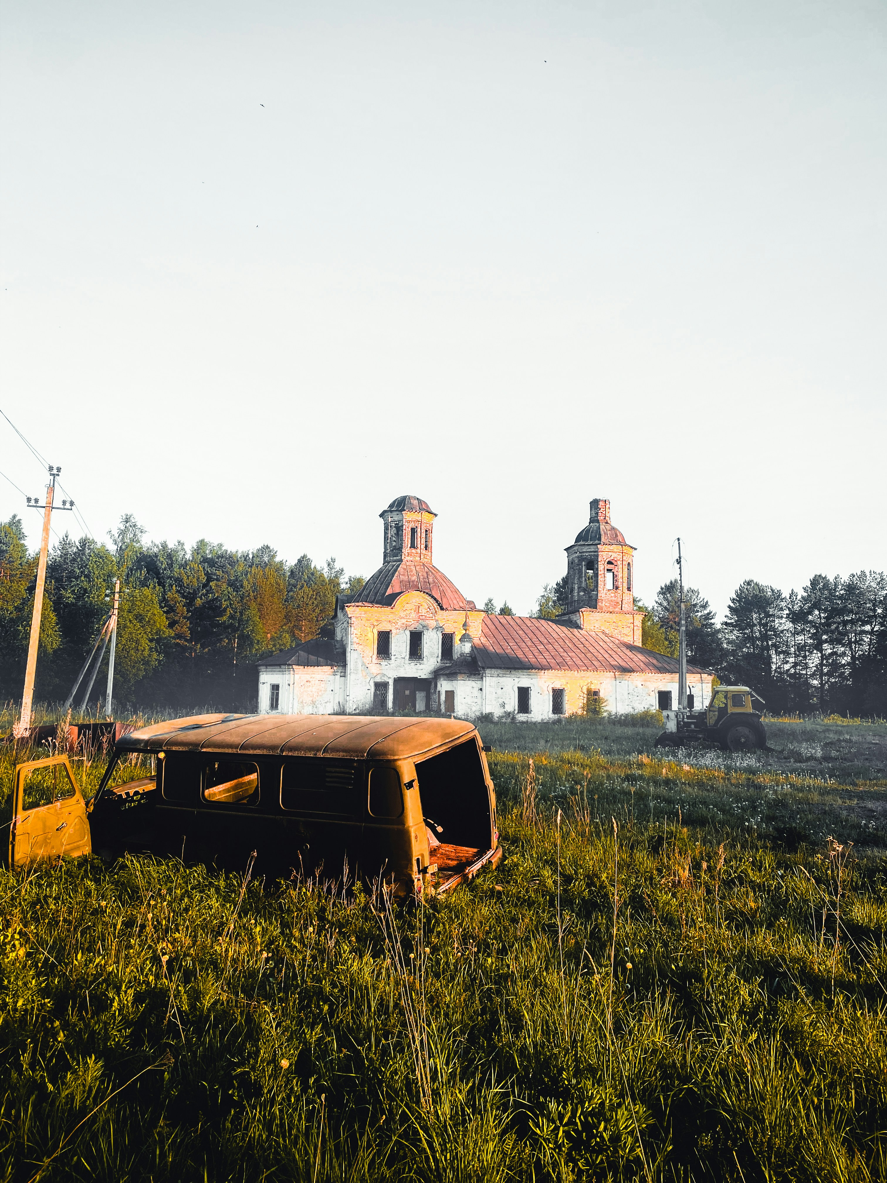 an old truck in a field with a building in the background
