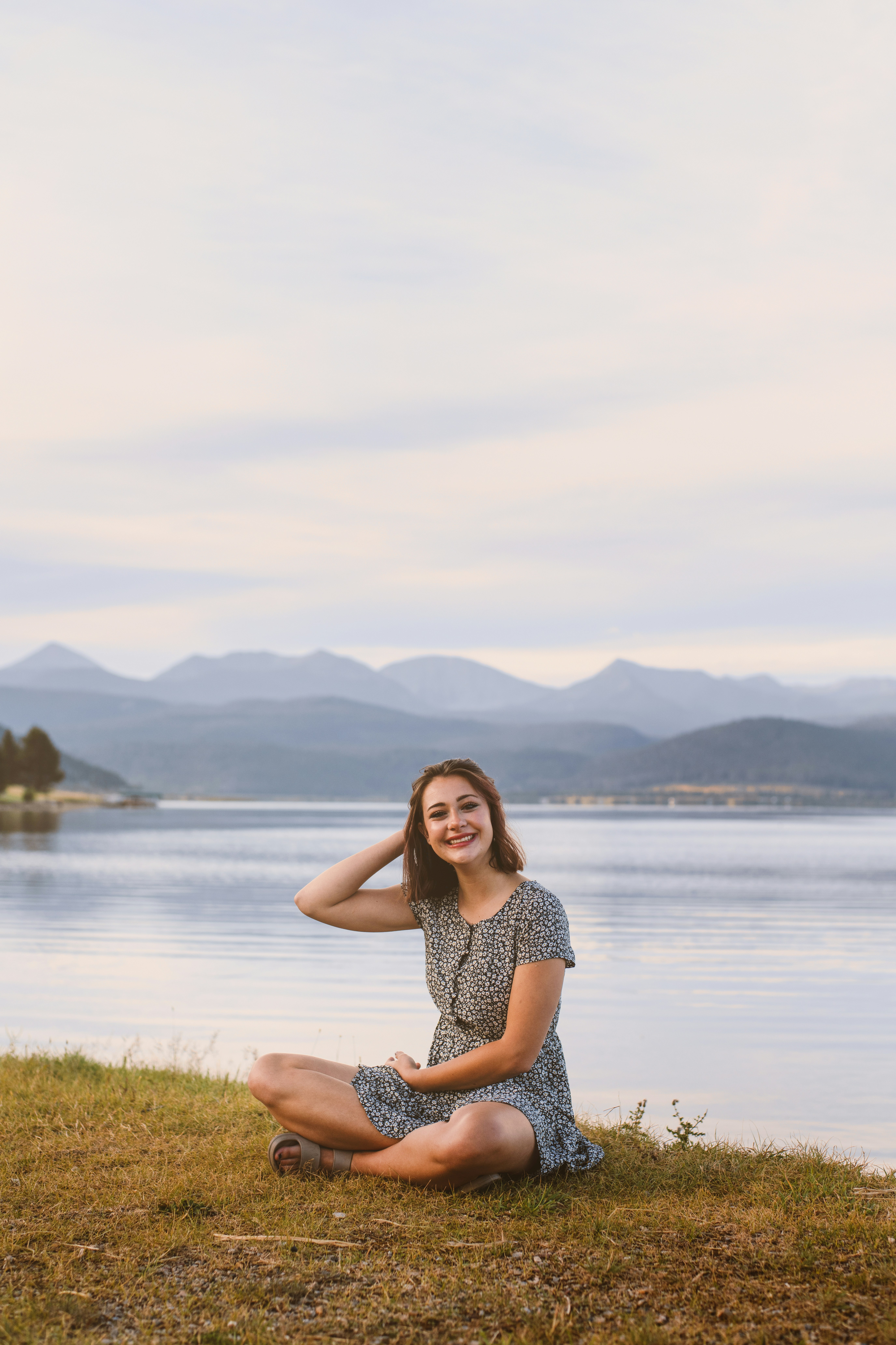 a woman sitting on the grass near a body of water