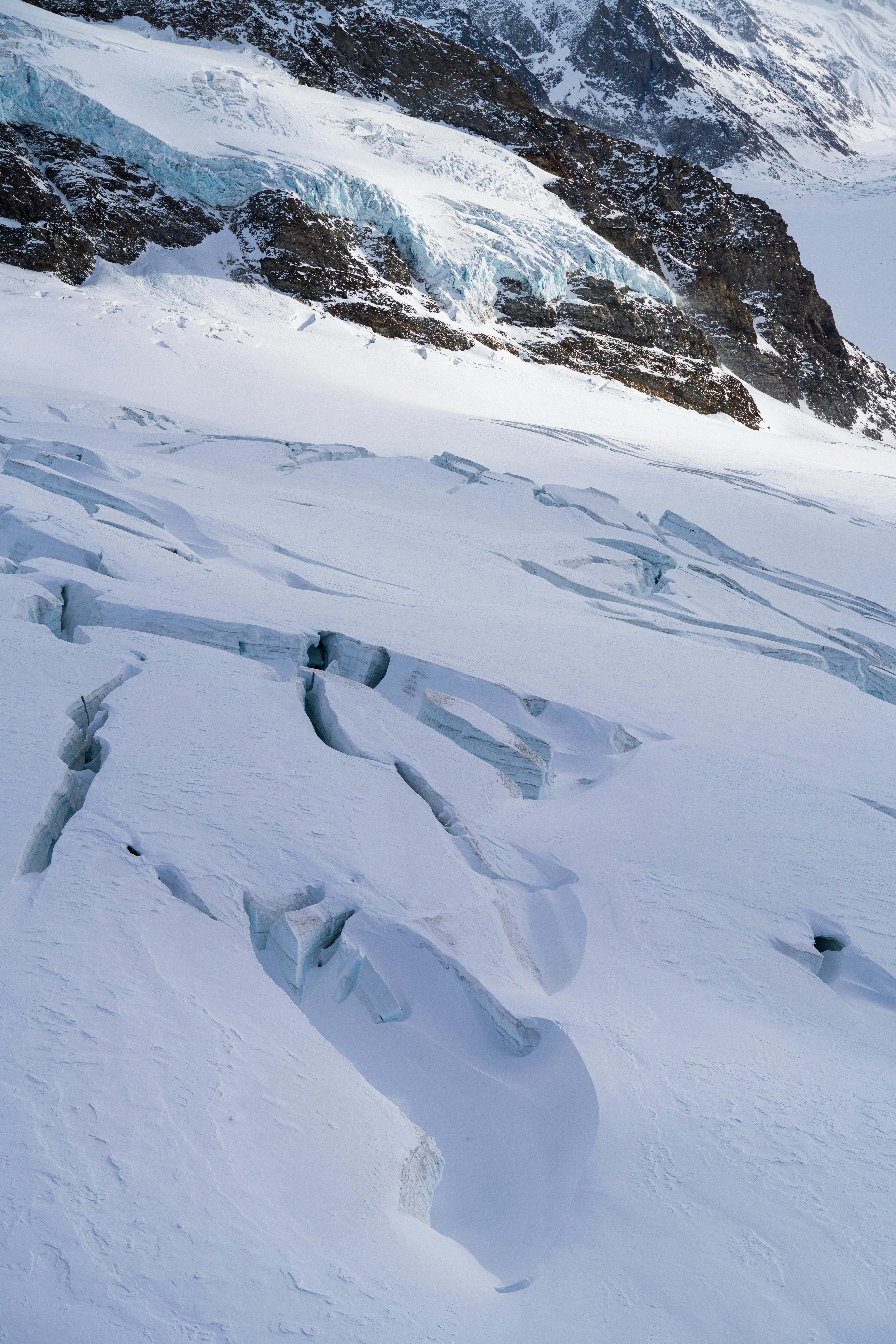 Azure Crevasse Corridor Across a Snowbound Glacier