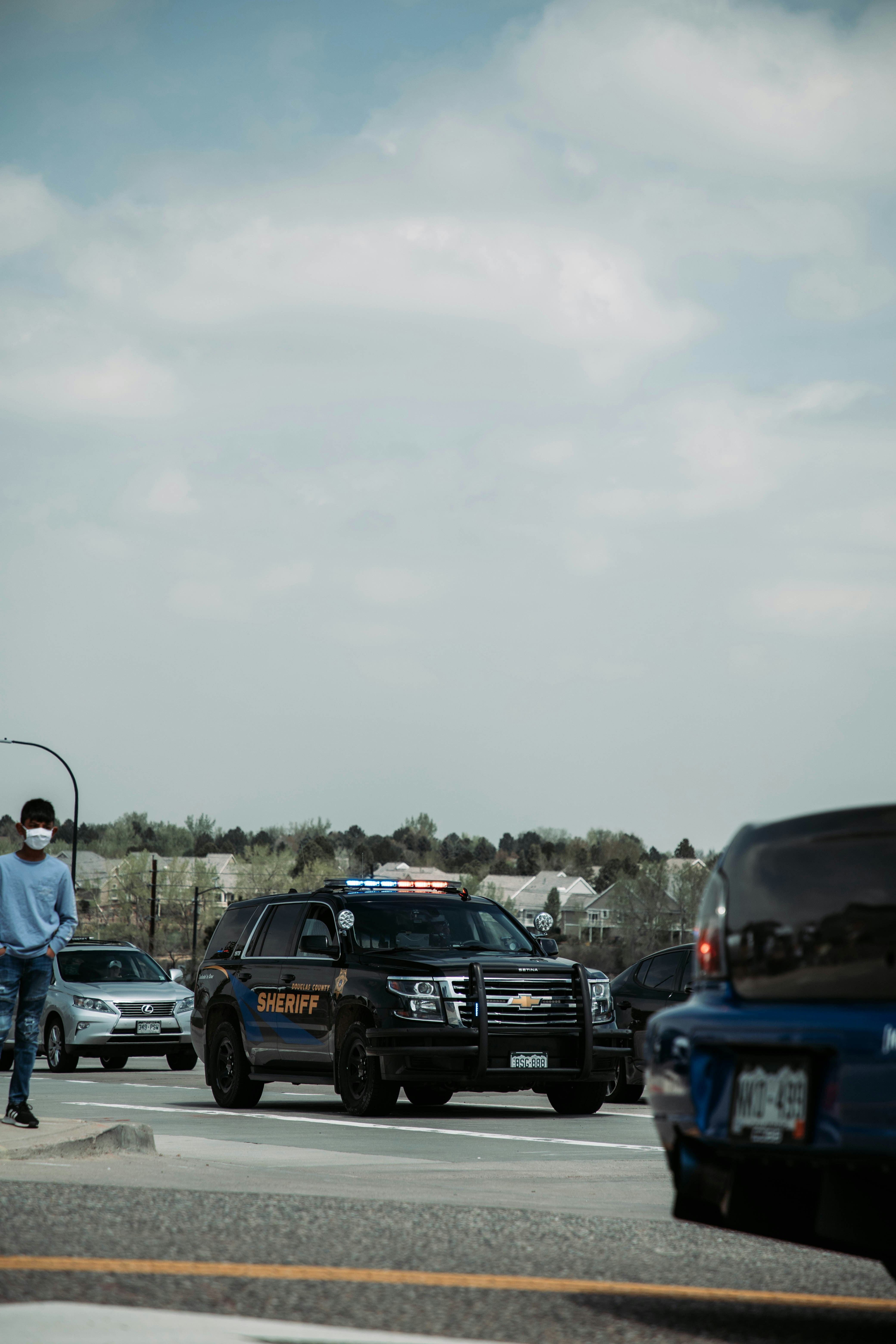 A police car driving down a street next to other cars photo – Free ...