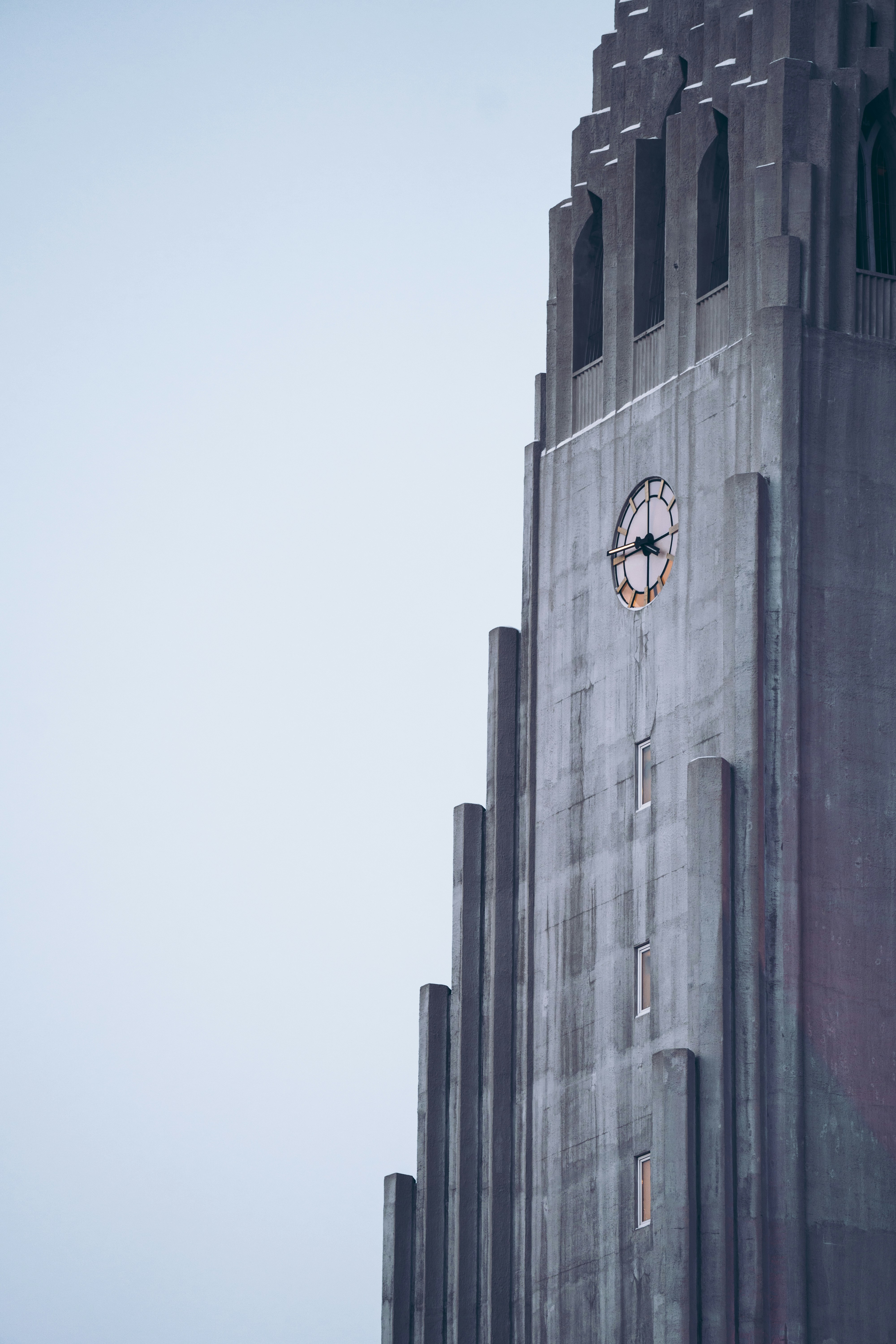 Tower Clockwatcher: A solemn concrete spire reaches the pale sky