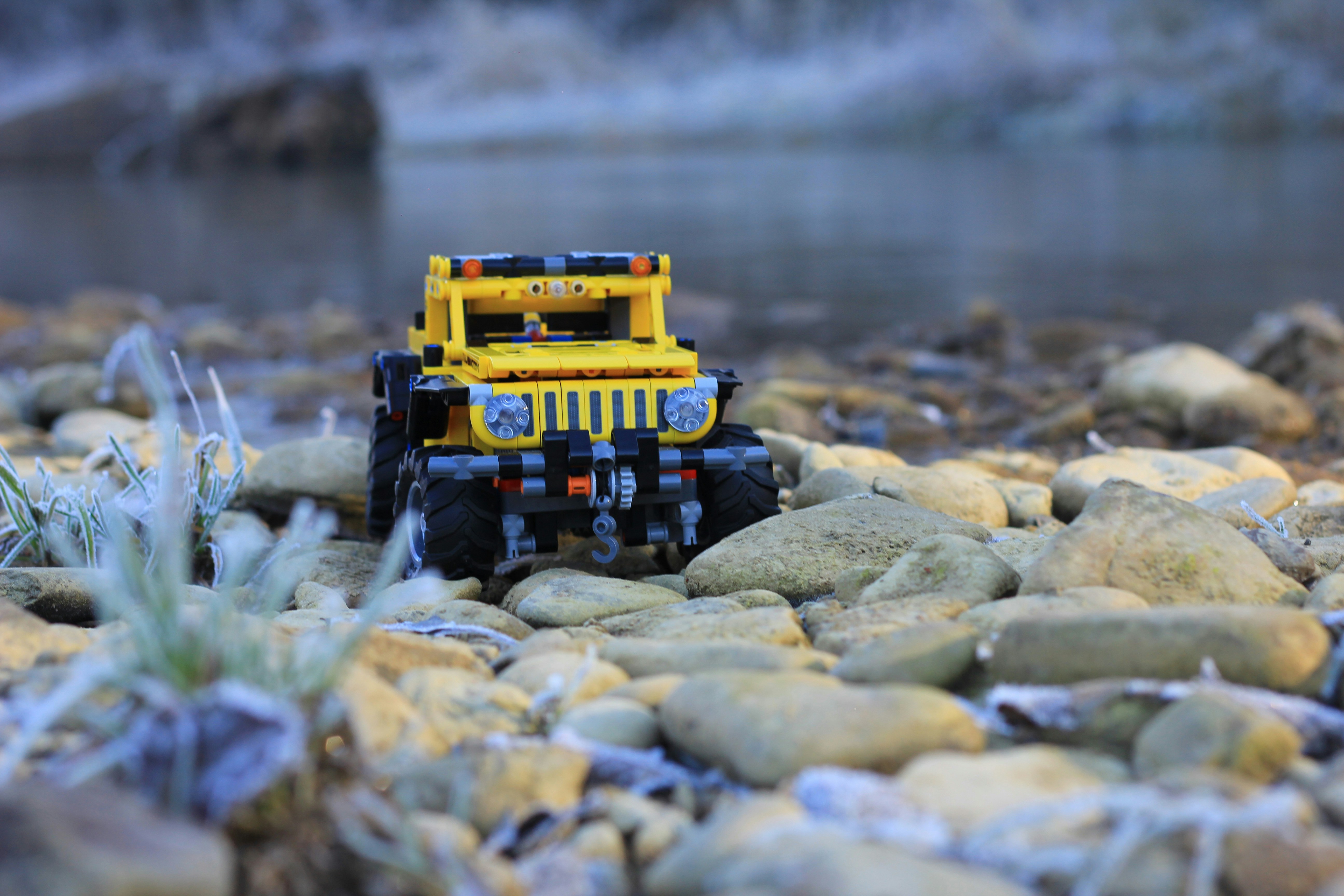 Rocky Riverside Rally: A Yellow Toy Jeep Anchored on Pebbles