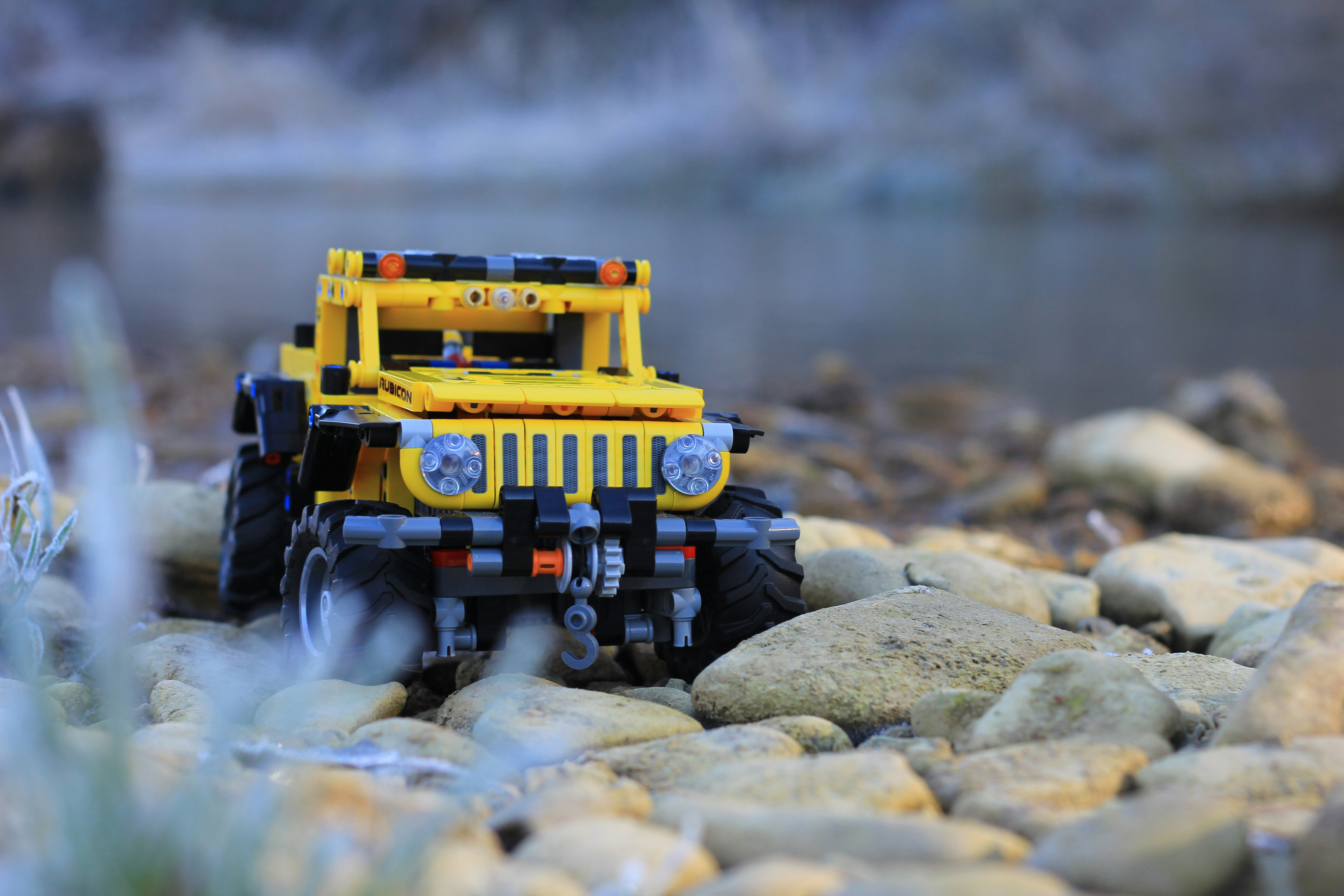Pebble Riverbank Patrol: Yellow LEGO Jeep by the Quiet Water