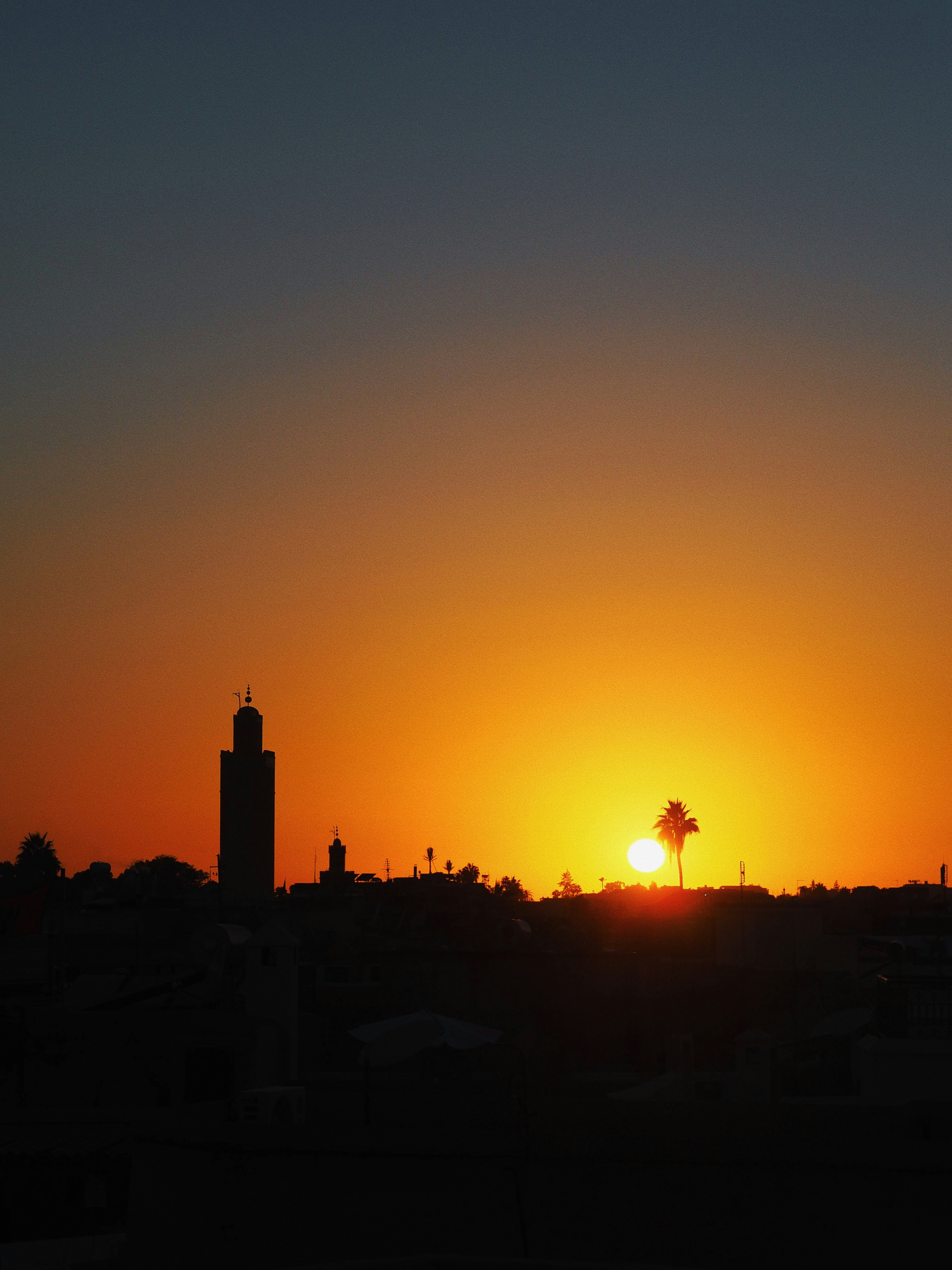 the sun is setting over a city with a clock tower