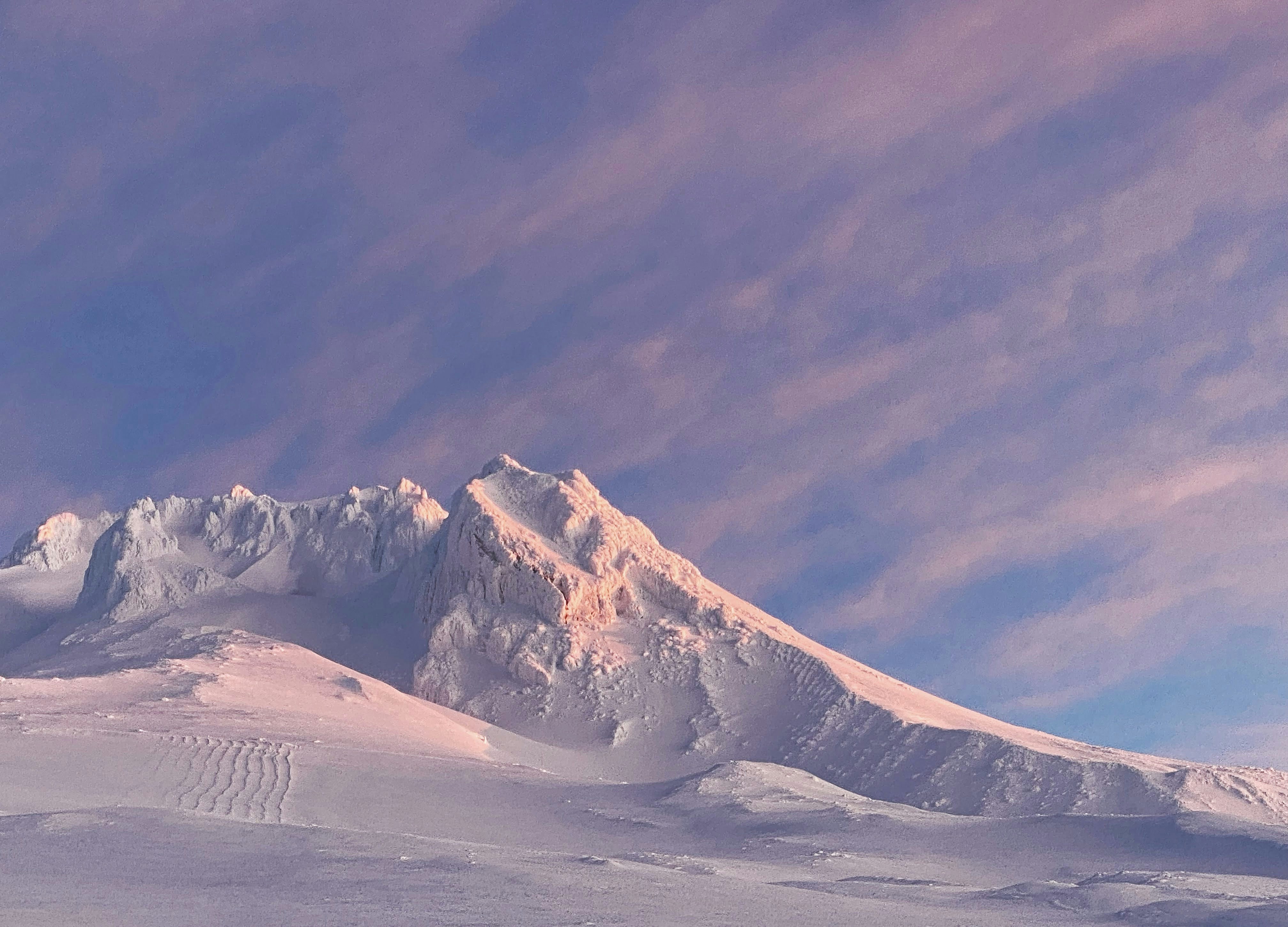 Snow-covered mountain with pink and blue sky at sunset.