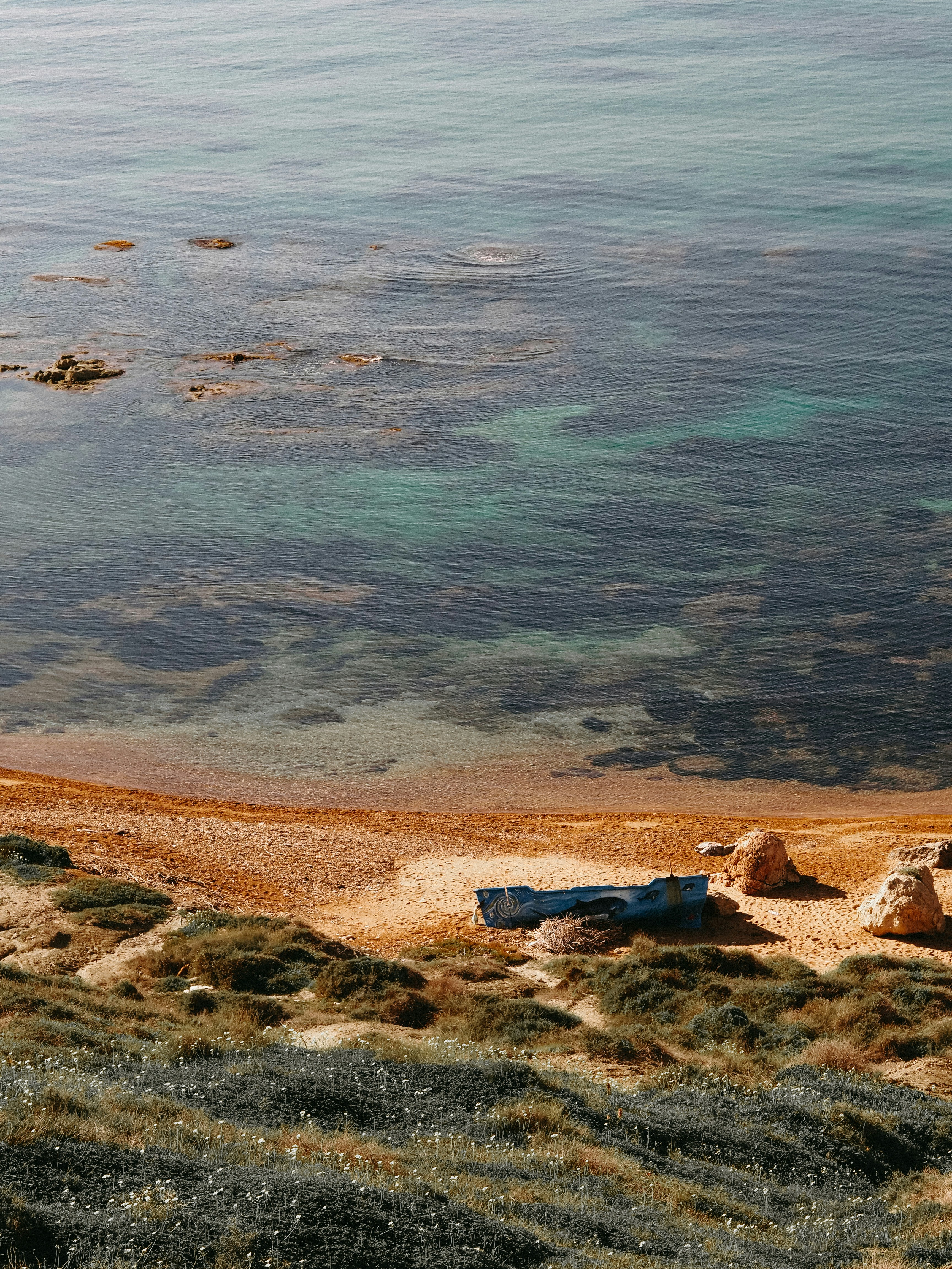 Blue Boat on a Pebbled Shore Beneath Turquoise Waters