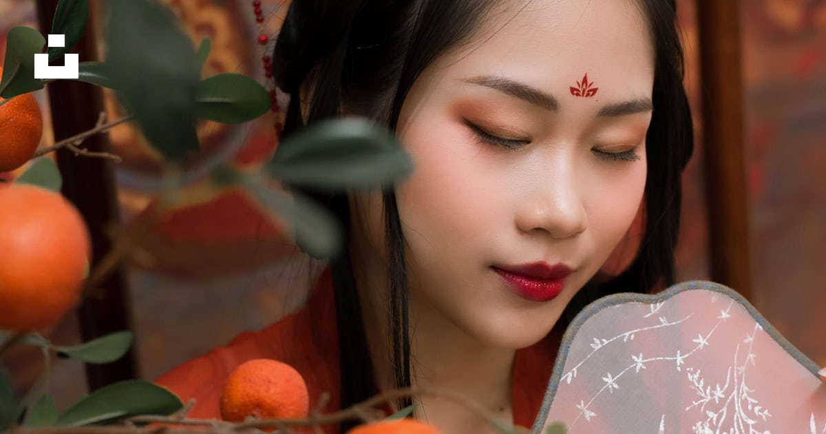 오렌지 다발 앞에서 부채를 들고 있는 여자 사진 Unsplash의 무료 한푸 이미지