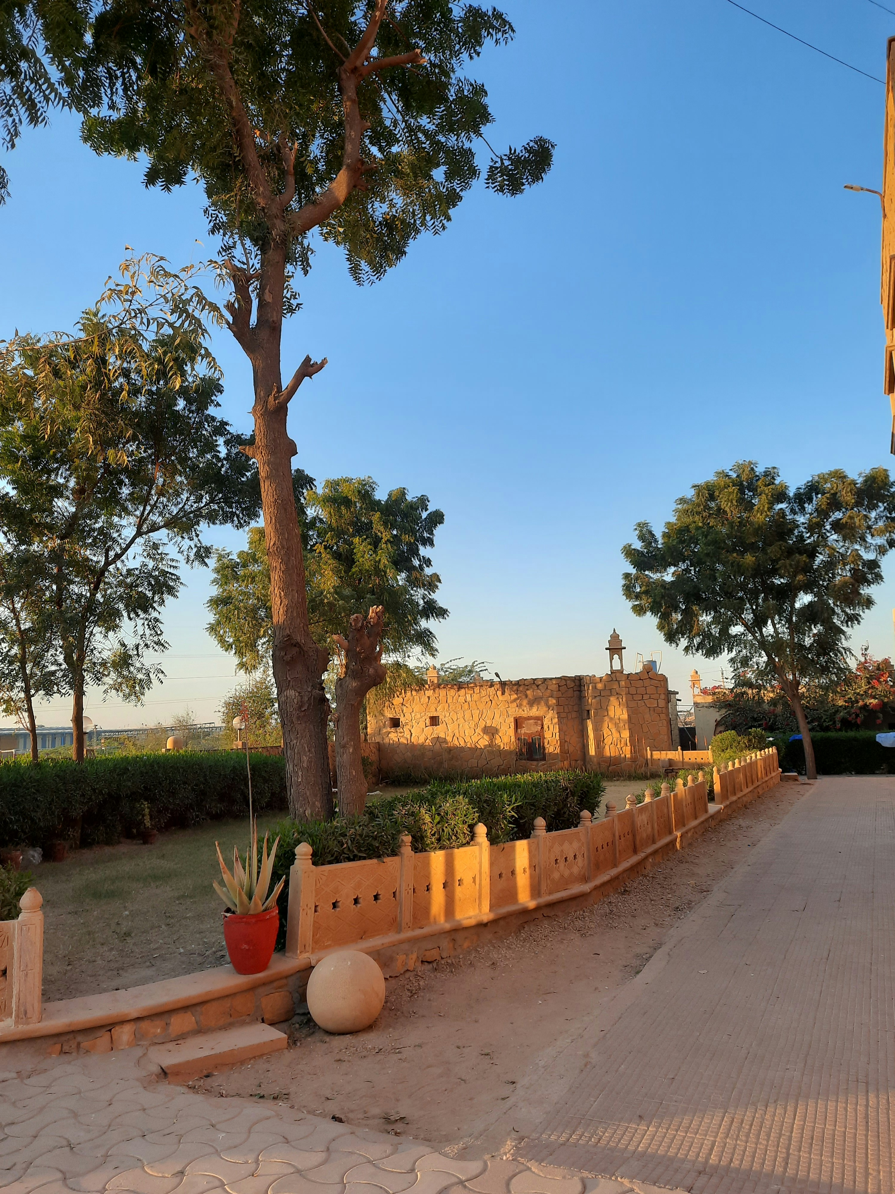 Sunlit promenade by a stone fortress under a clear afternoon sky