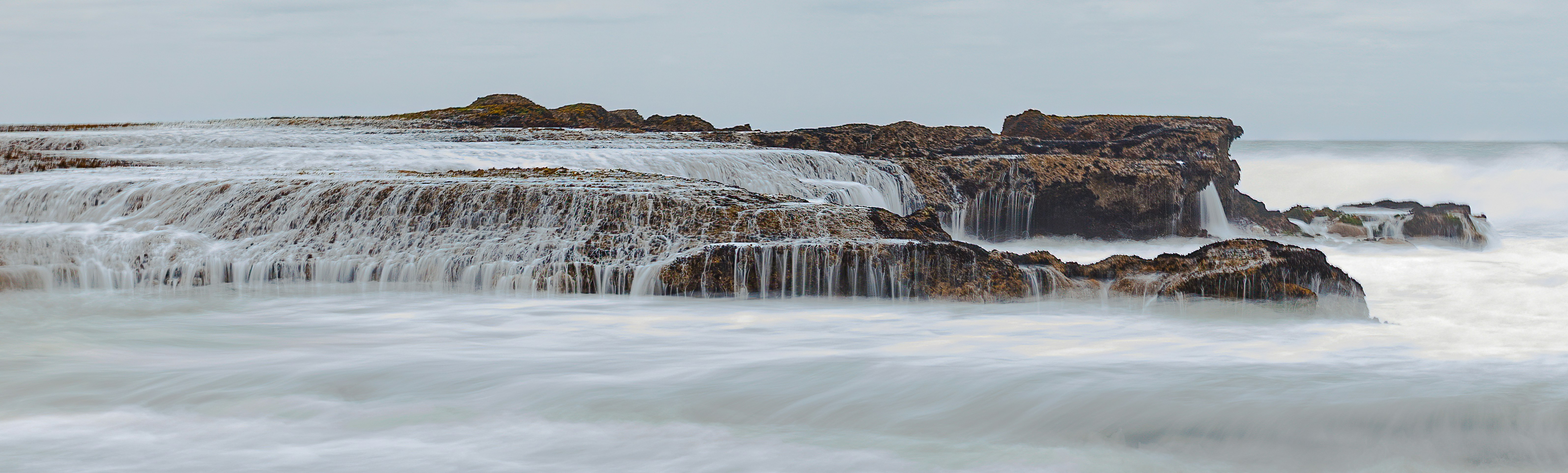 A large body of water surrounded by rocks photo – Free Water Image on ...