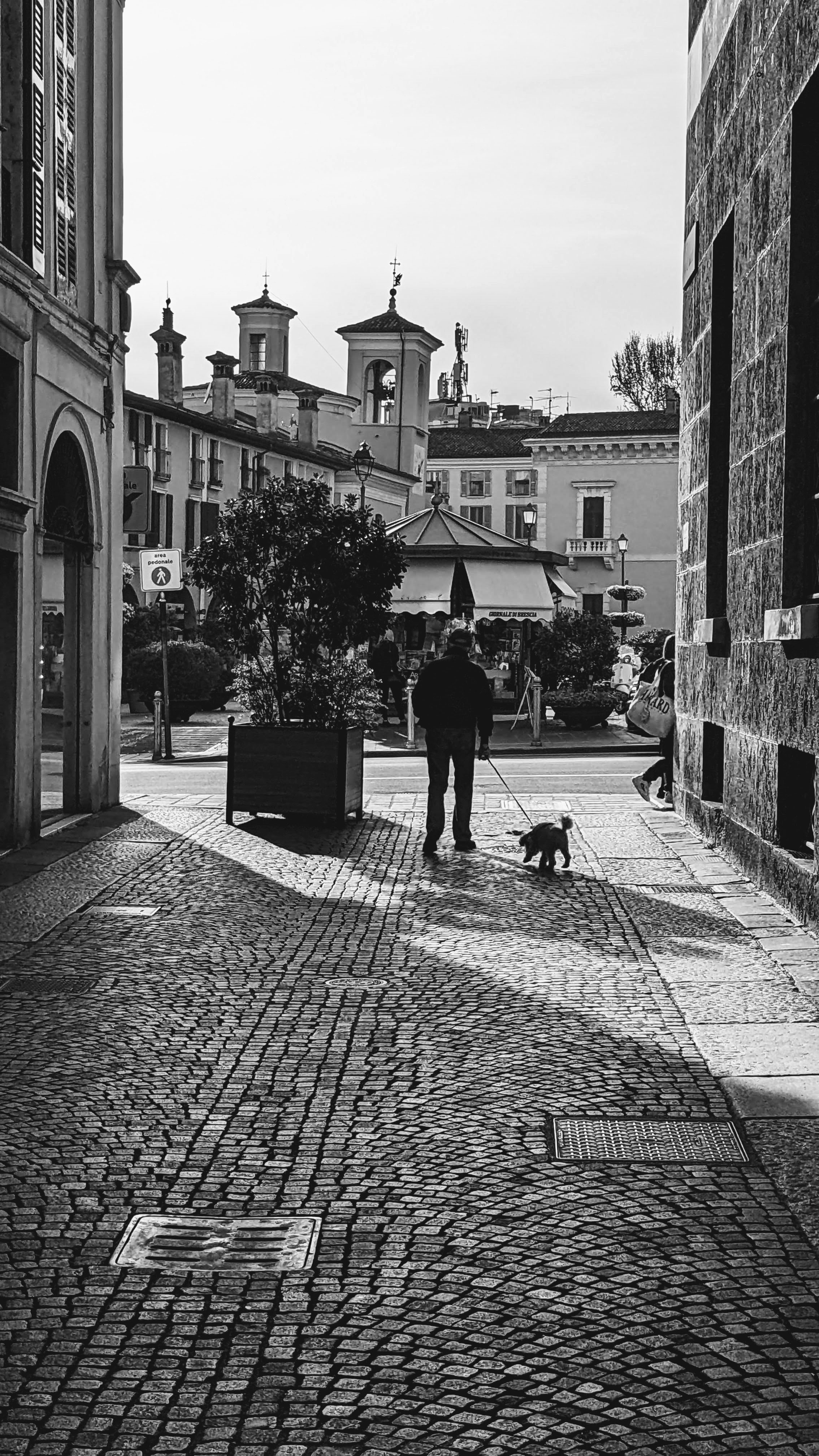 a black and white photo of a man walking his dog