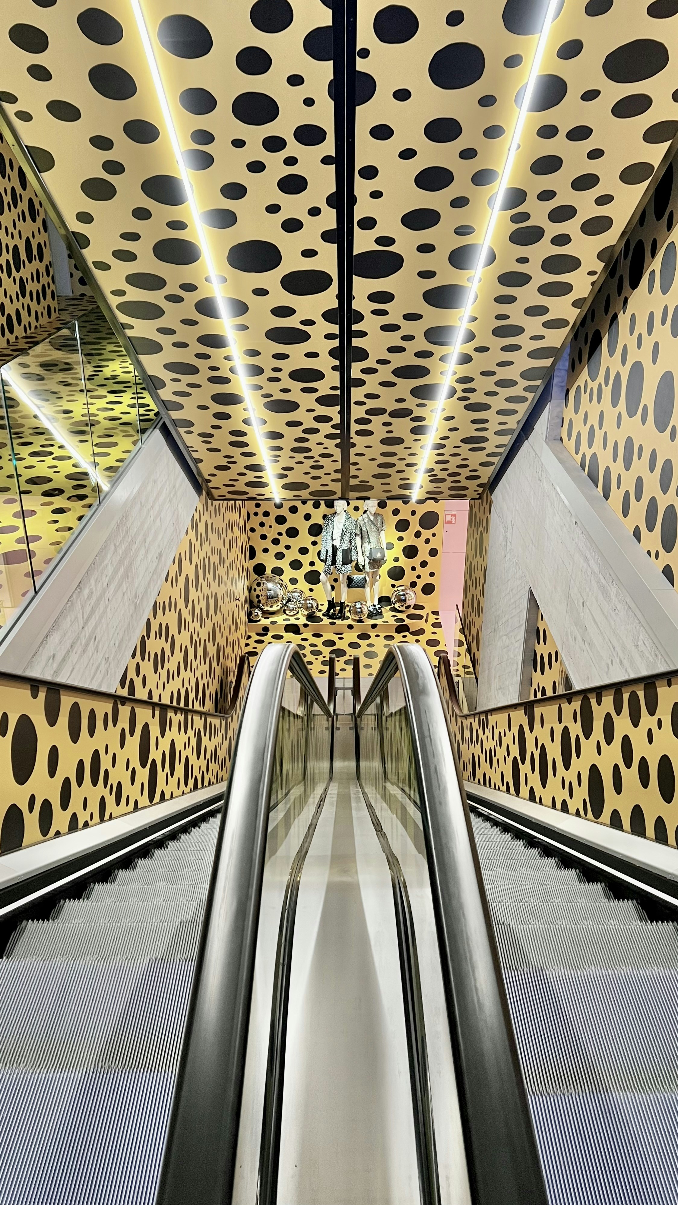 Polka-Dot Ascent: Escalator Through a Neon Fashion Corridor
