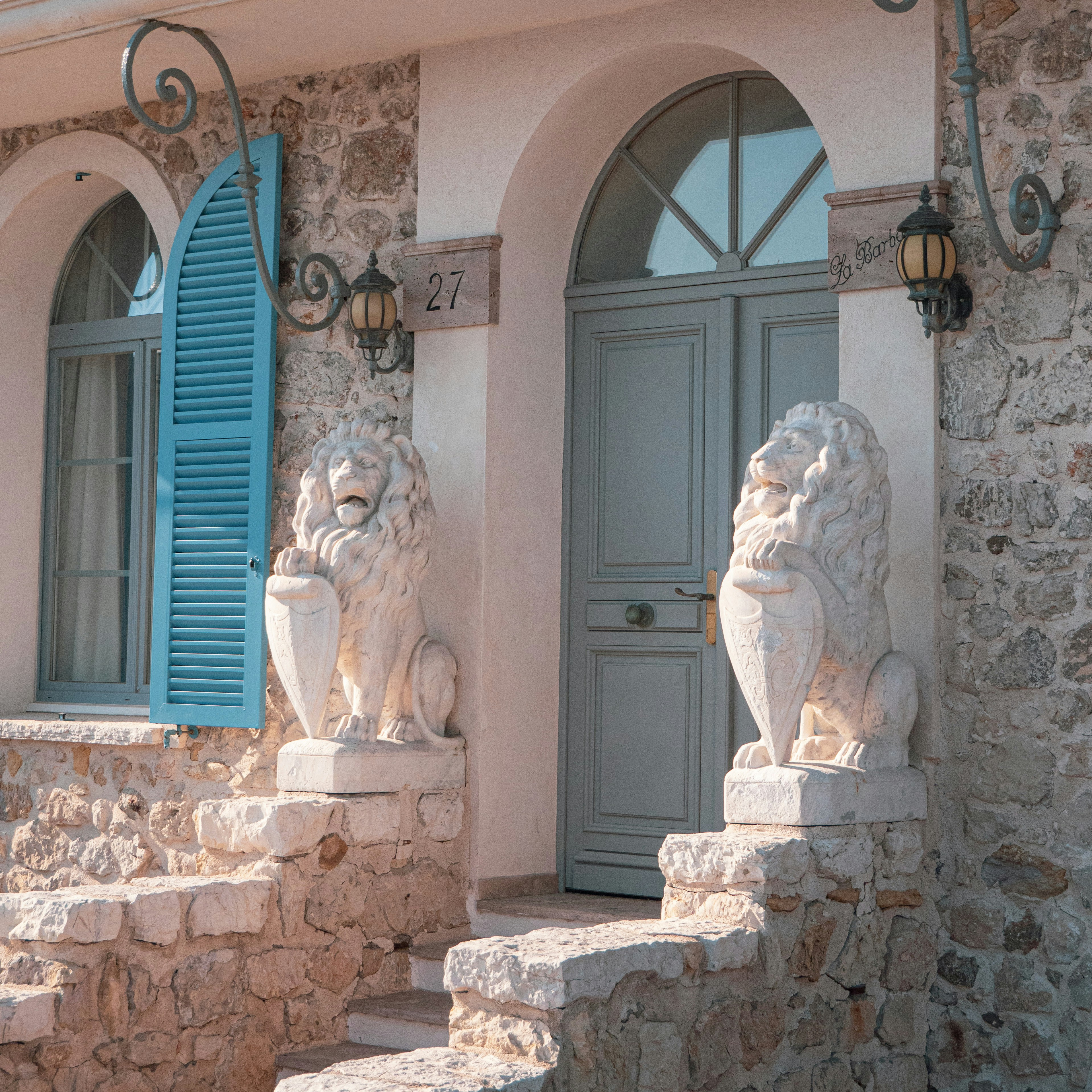 Lions at the Threshold: Turquoise Door Framed by Sunlit Stone