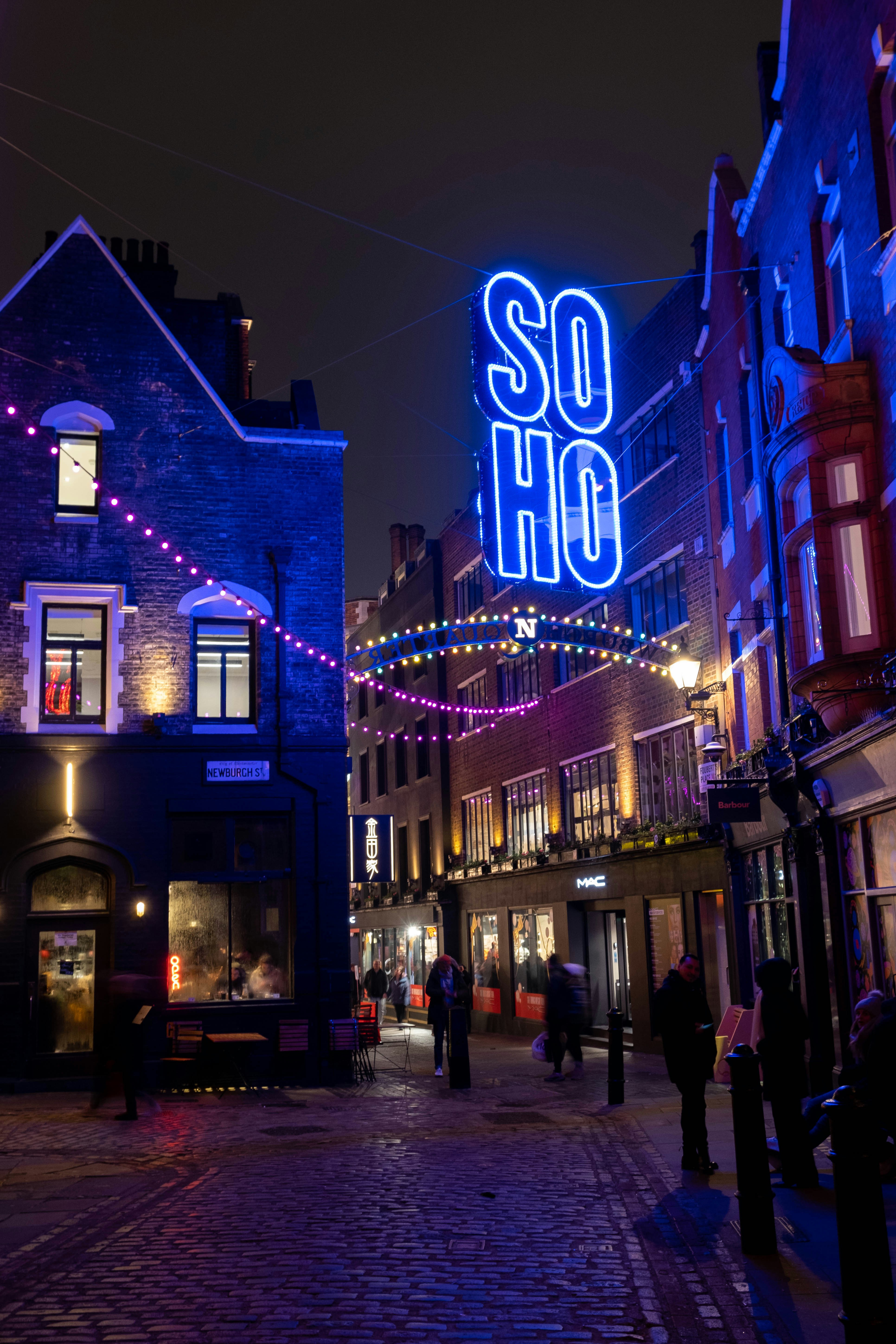 A city street at night with a neon sign photo – Free London Image on ...