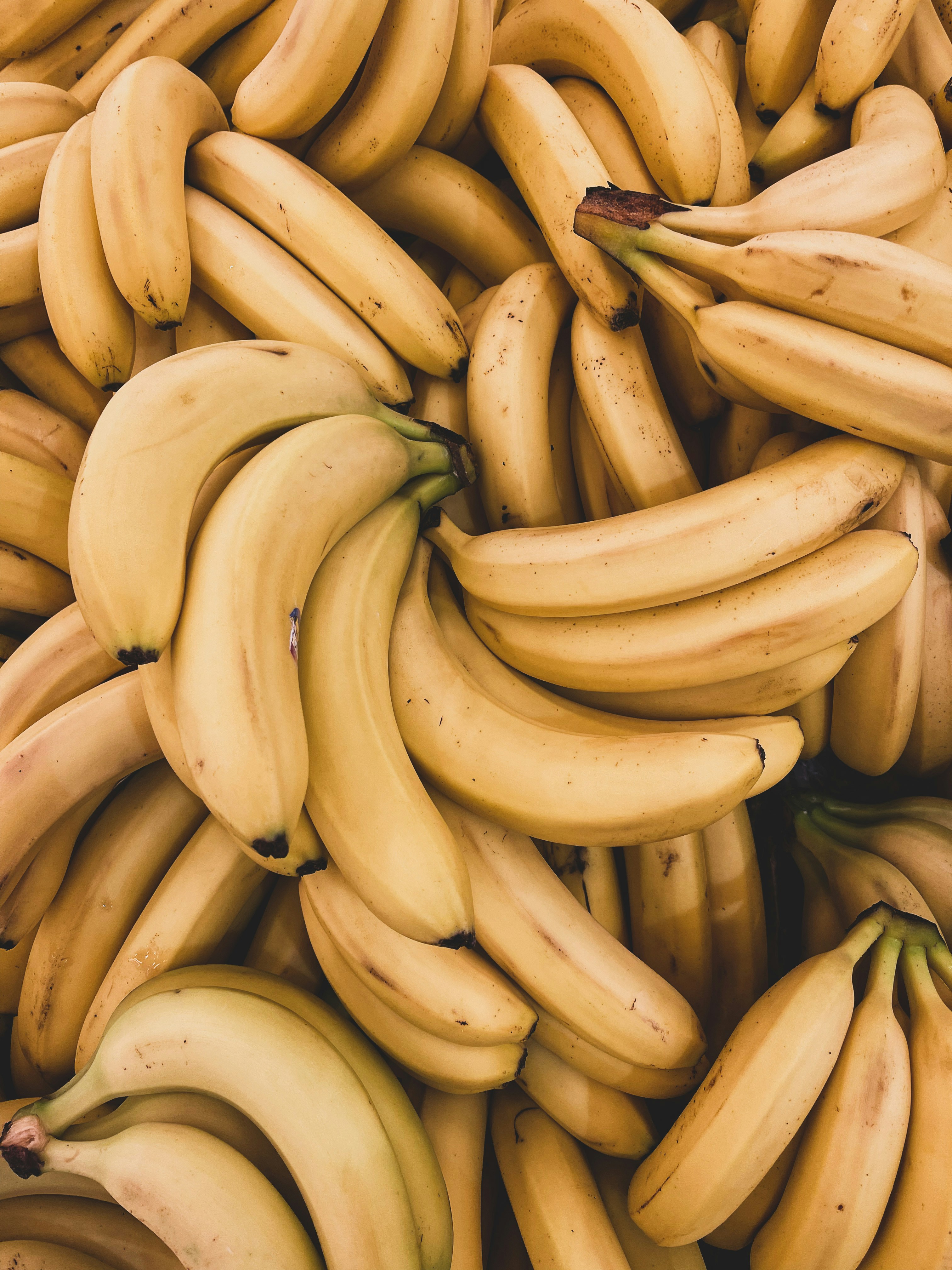 A vibrant collection of ripe bananas stacked together, showcasing their smooth, yellow skins and natural curves.