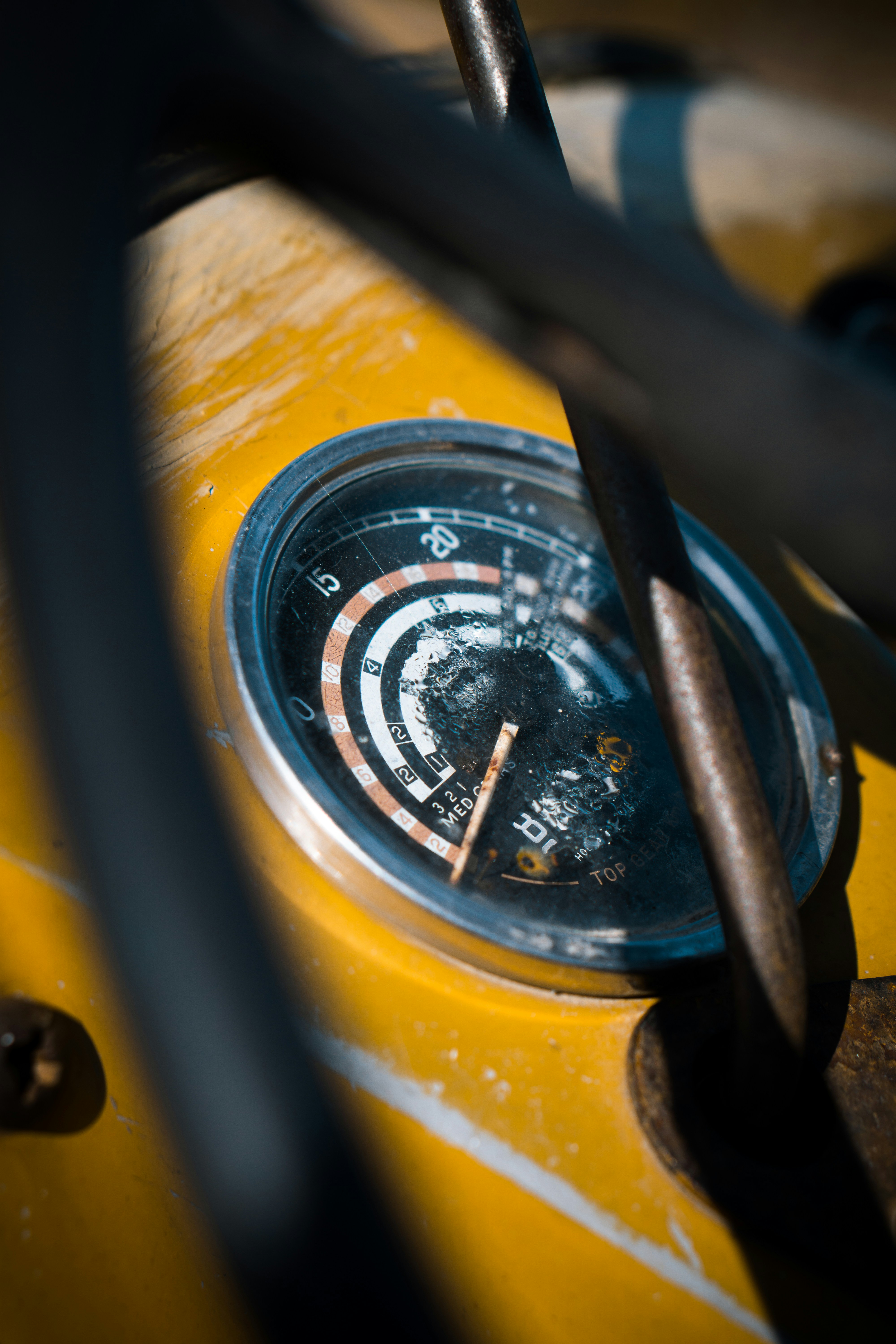 The Weathered Dial: Close-Up on a Yellow Industrial Gauge Entangled with Cables