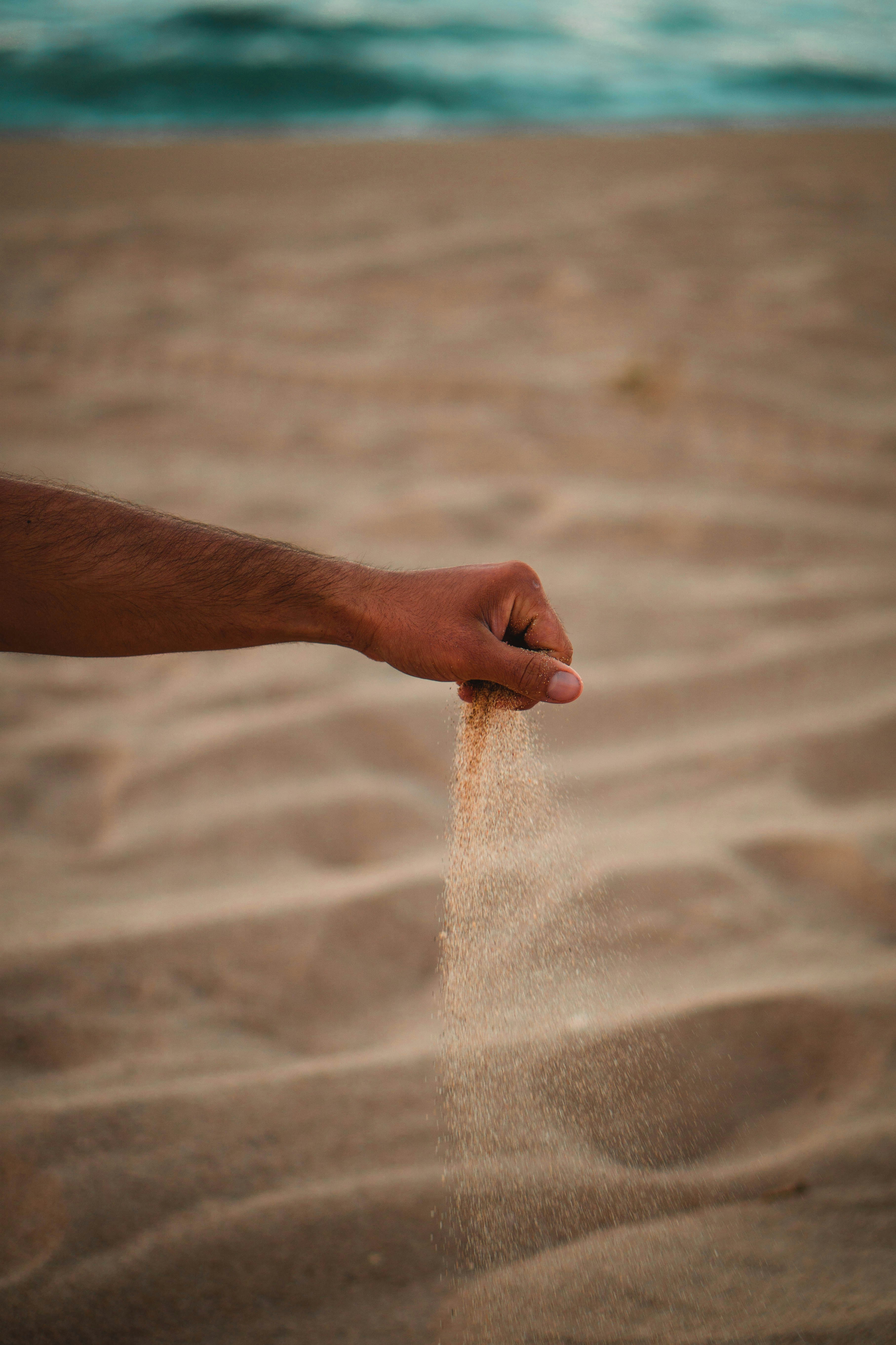A hand is sprinkling sand on a beach photo – Free Nature Image on Unsplash