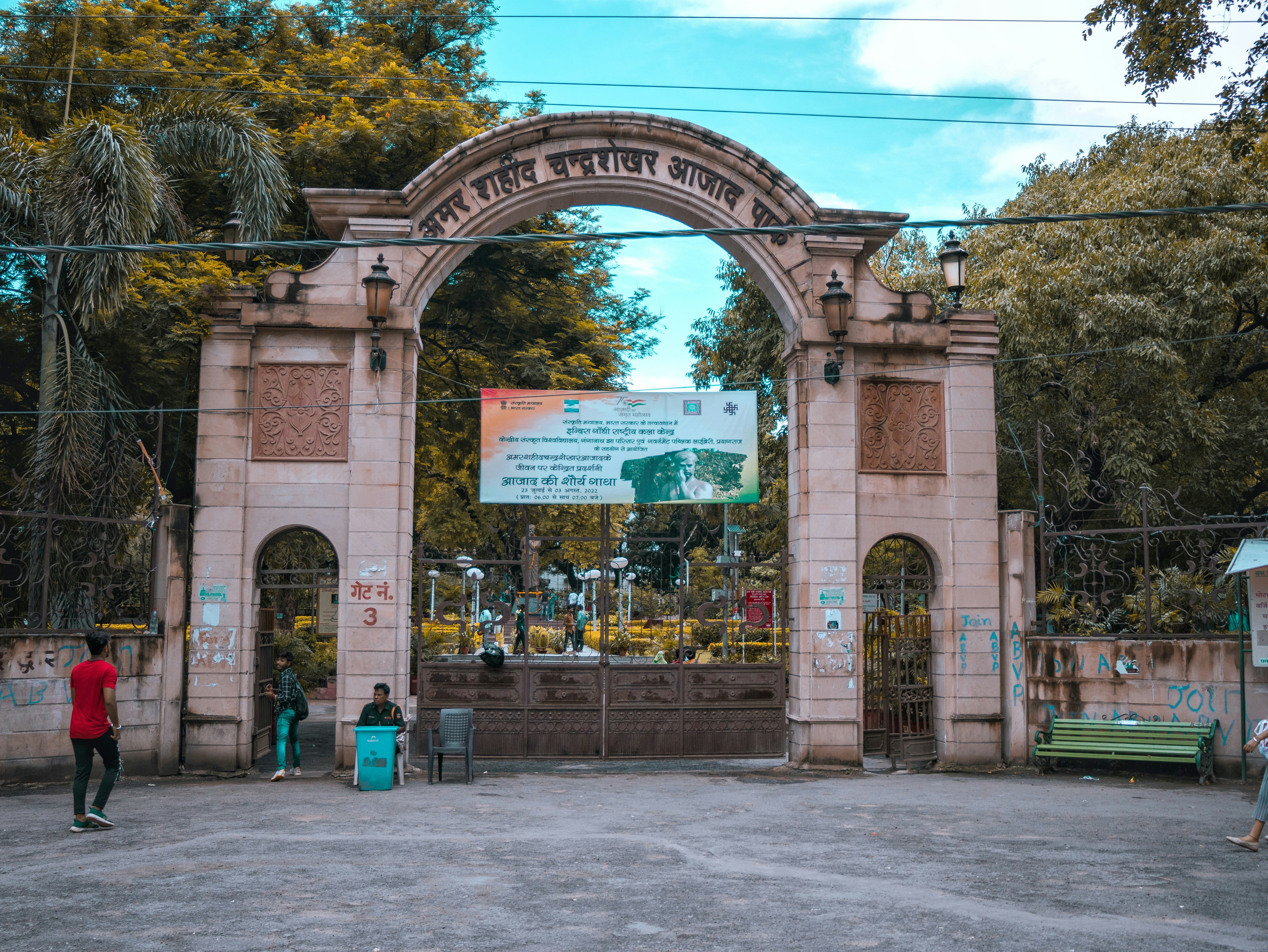 Gateway in Stone: A Park Arch Framed by Foliage and a Banner