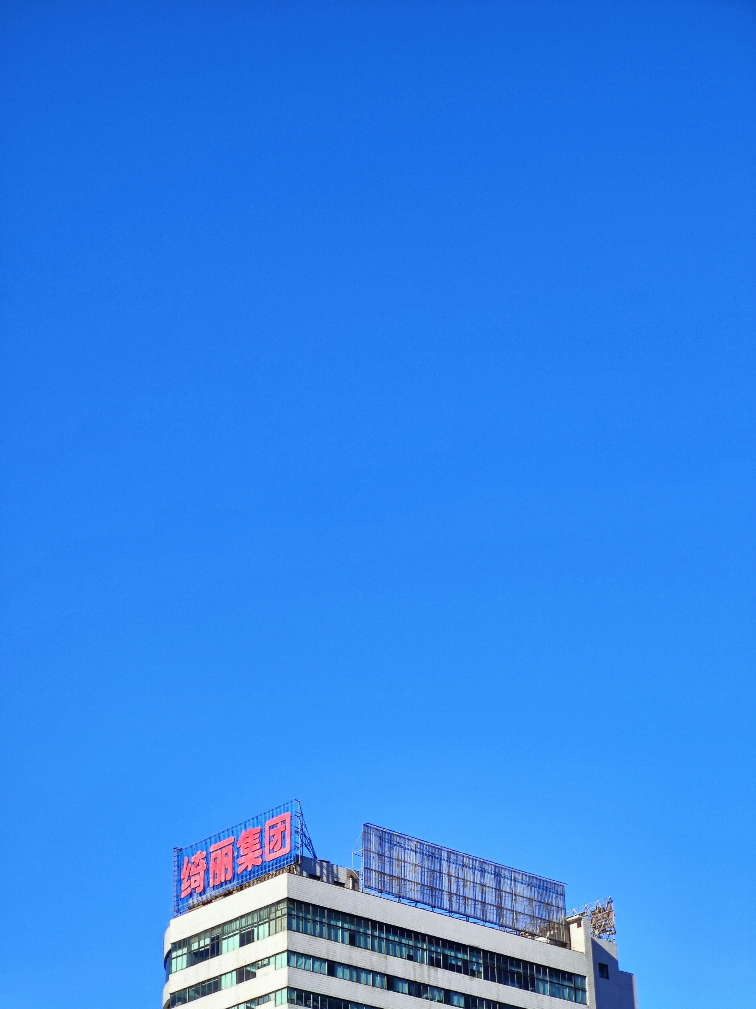 A vibrant building with a prominent sign stands against a bright blue sky, showcasing modern architecture and urban life.