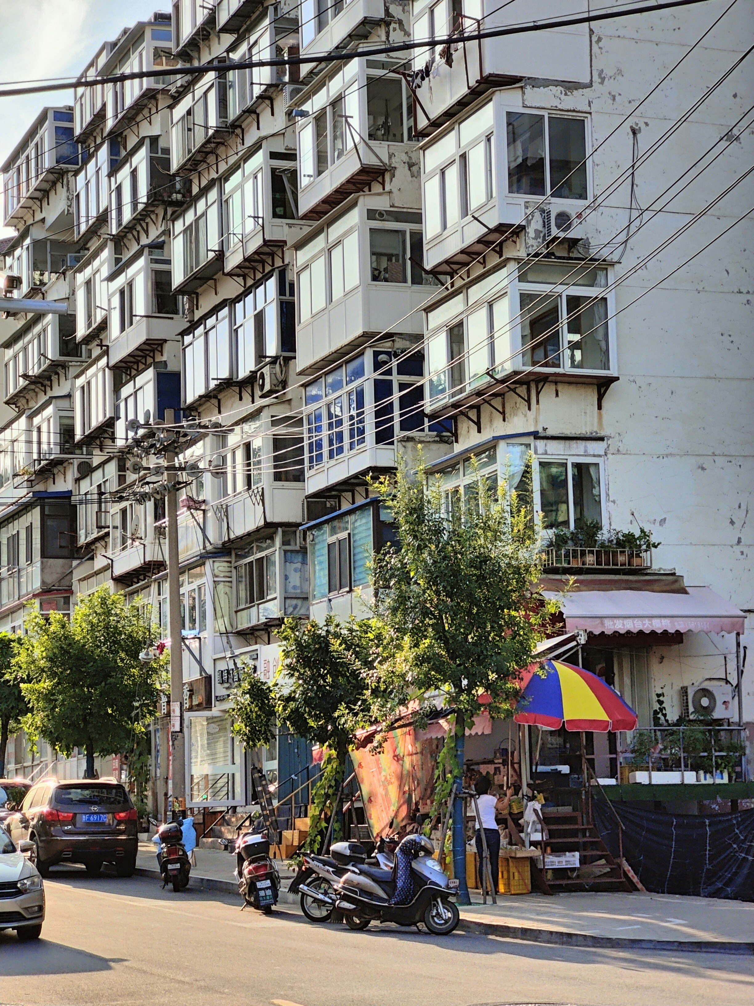 A vibrant street scene featuring a unique blend of modern architecture and local life, showcasing a lively market under colorful awnings.