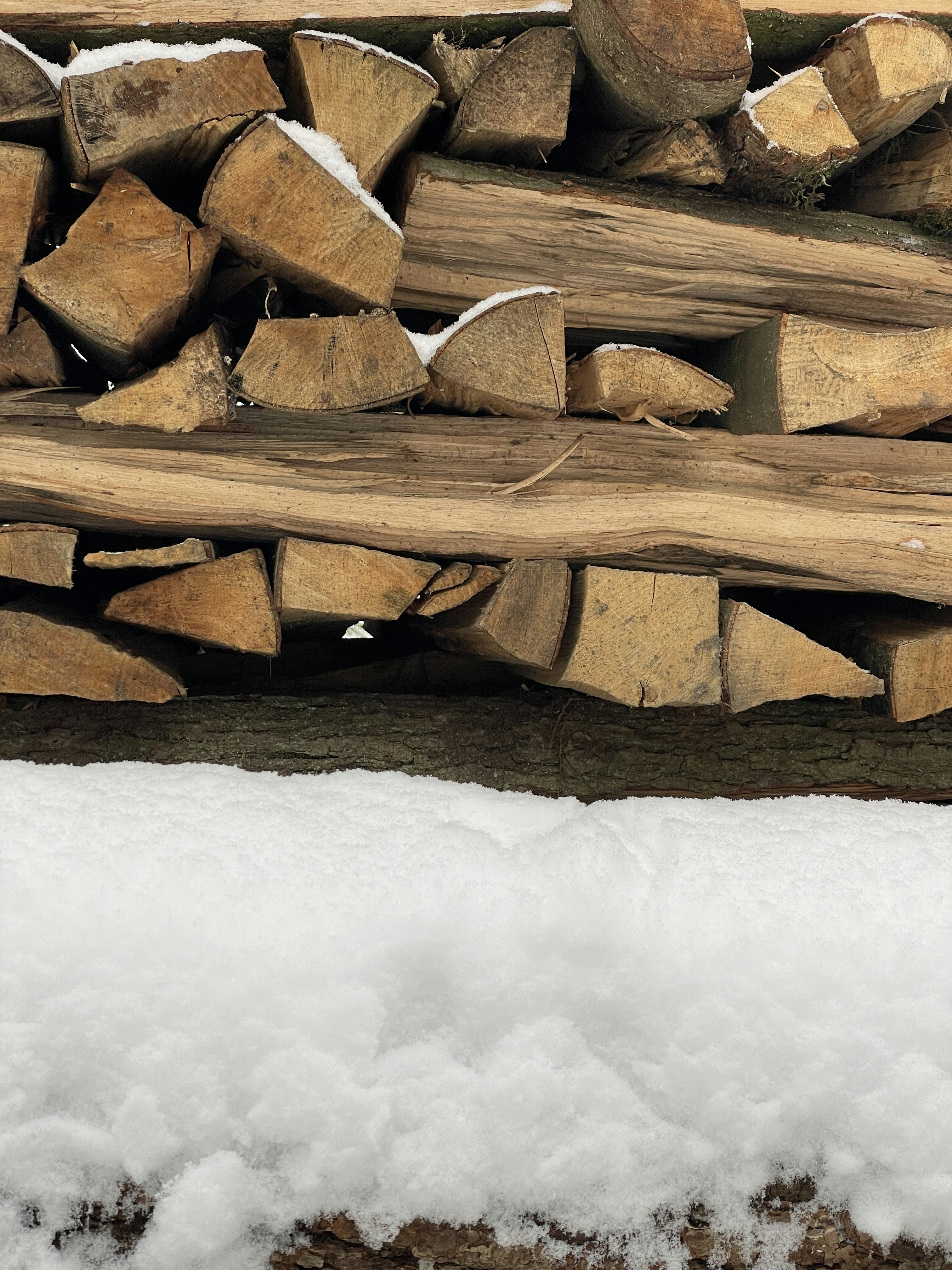 a pile of wood sitting next to a pile of snow