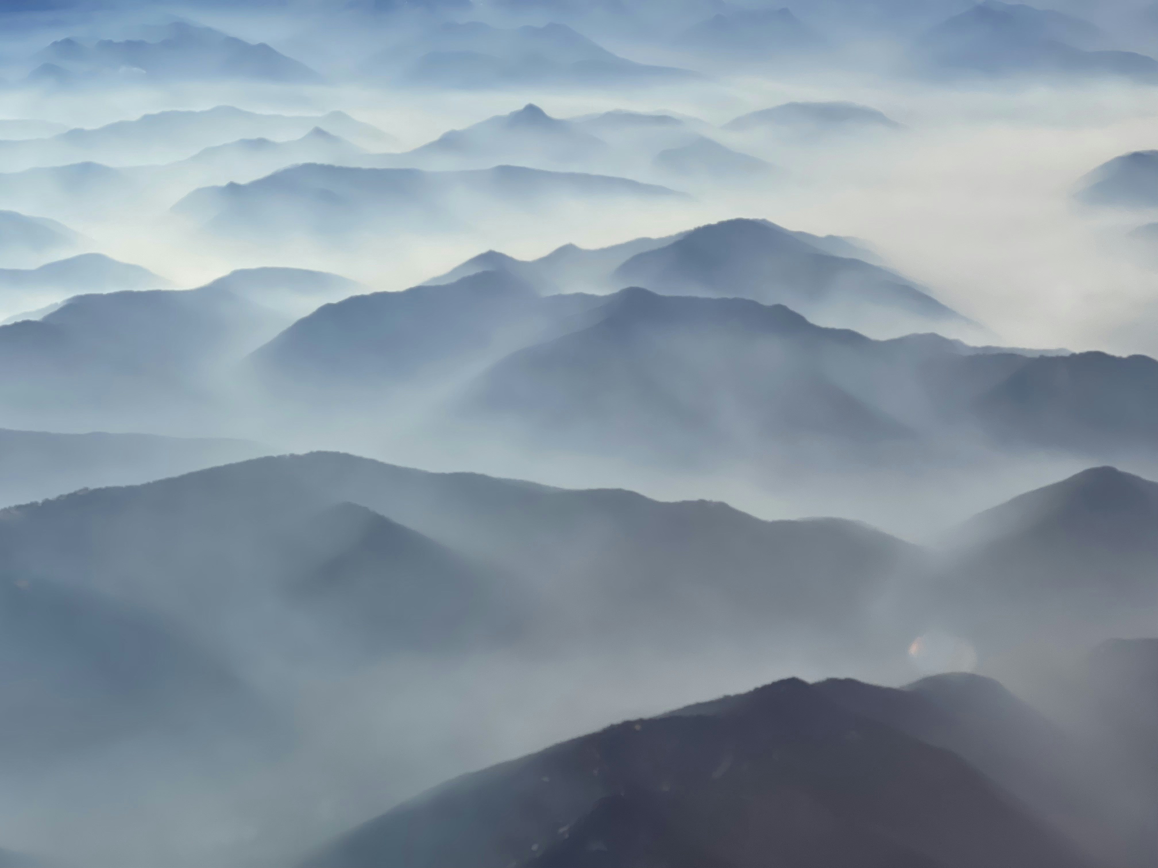Whispers in the Blue: Layered Mountain Ridges Draped in Fog