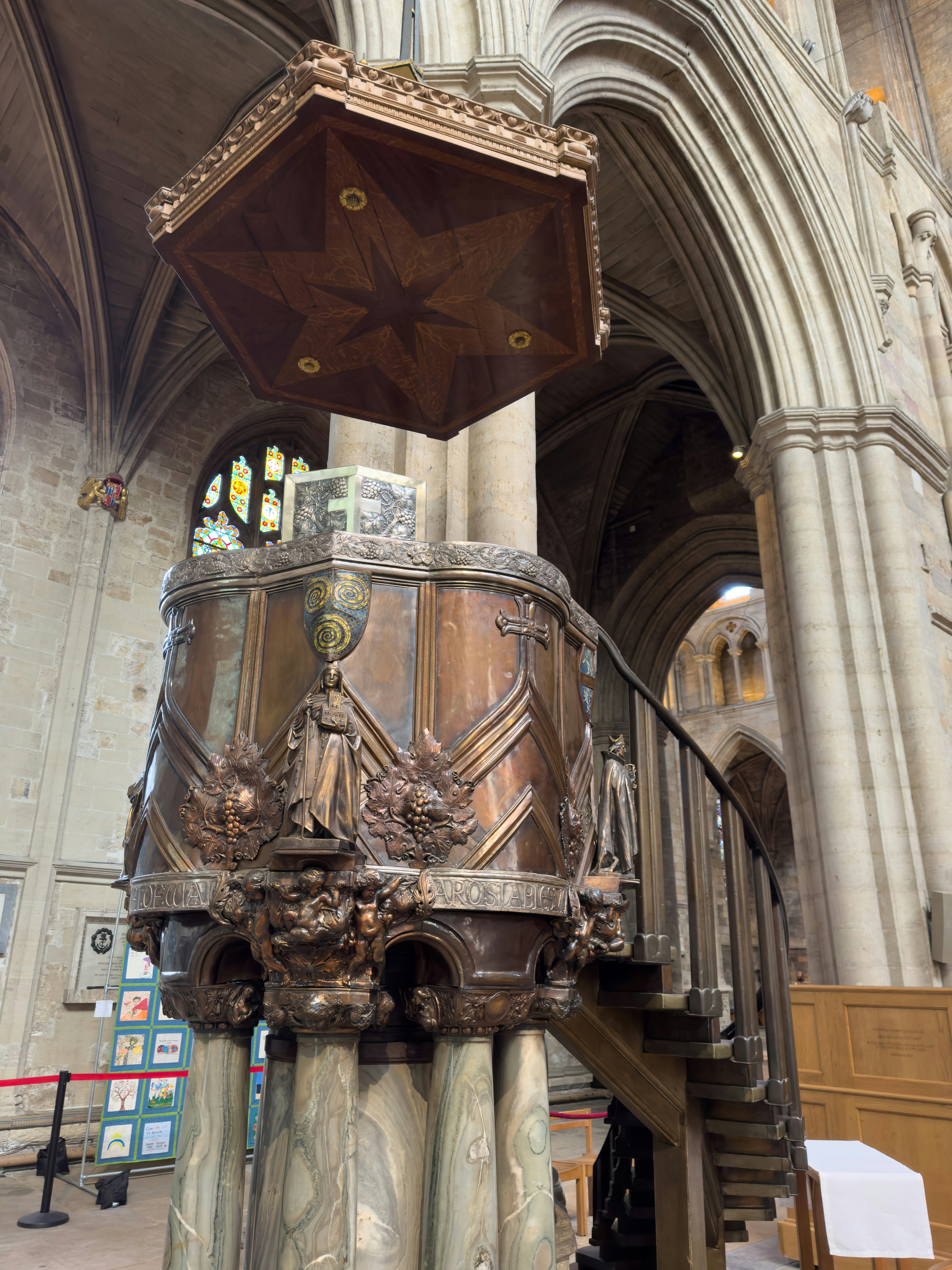 Intricately designed wooden pulpit featuring detailed carvings and an elegant stairway, set within a grand cathedral interior.