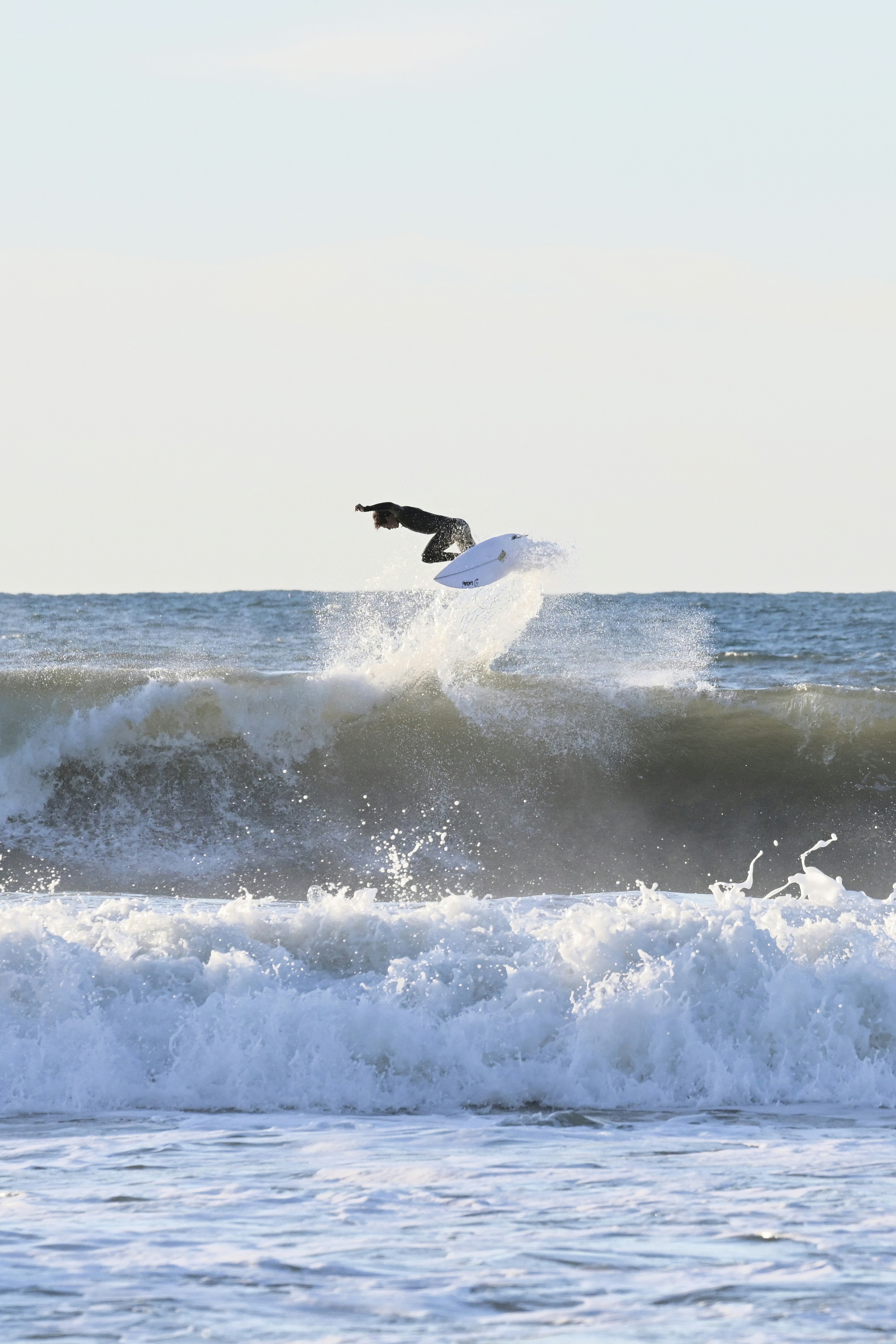 A surfer defies a curling ocean crest mid-air over a breaking wave