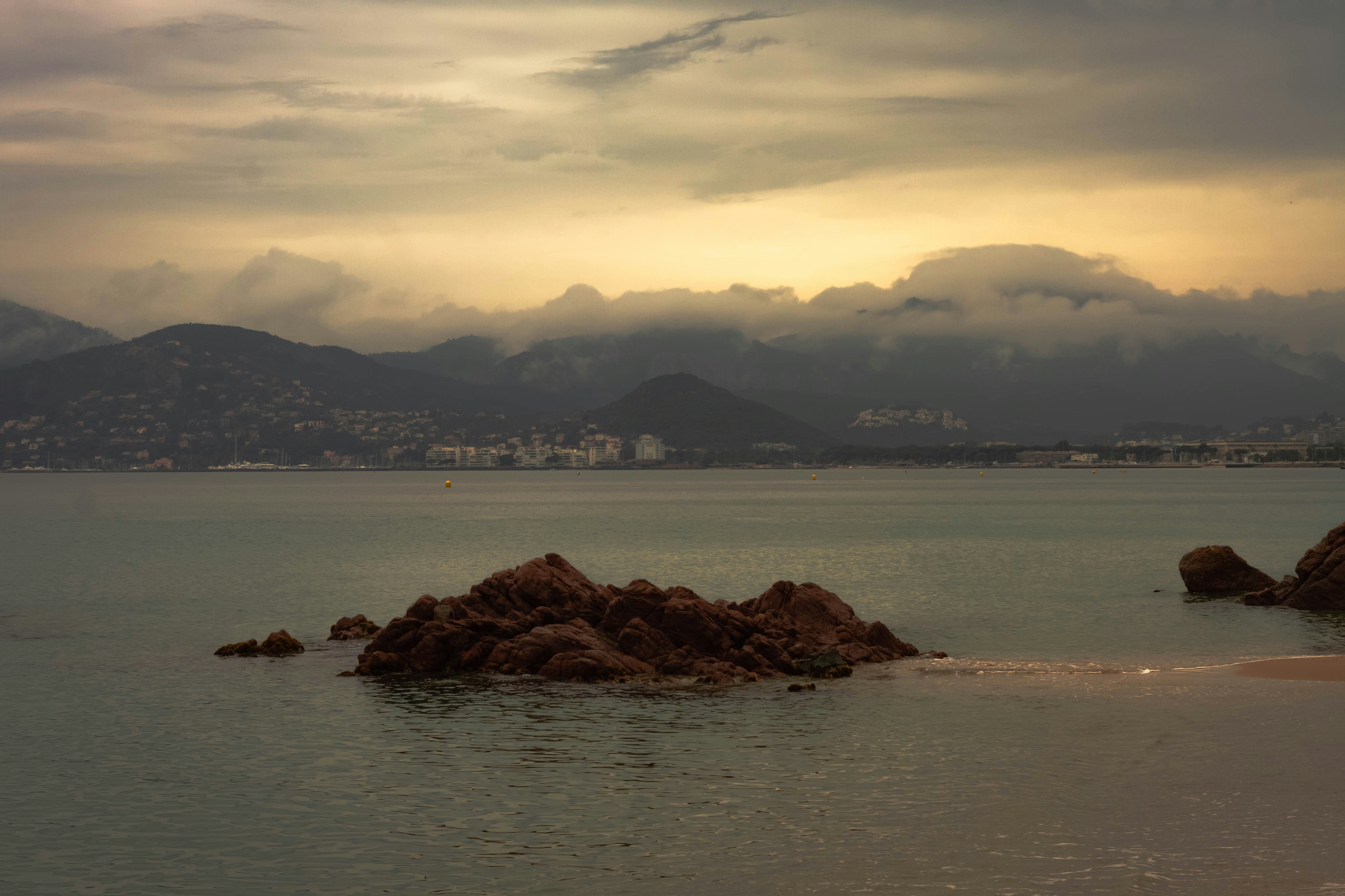 Rocky Seabed at Dusk: Calm Waters and Distant Town