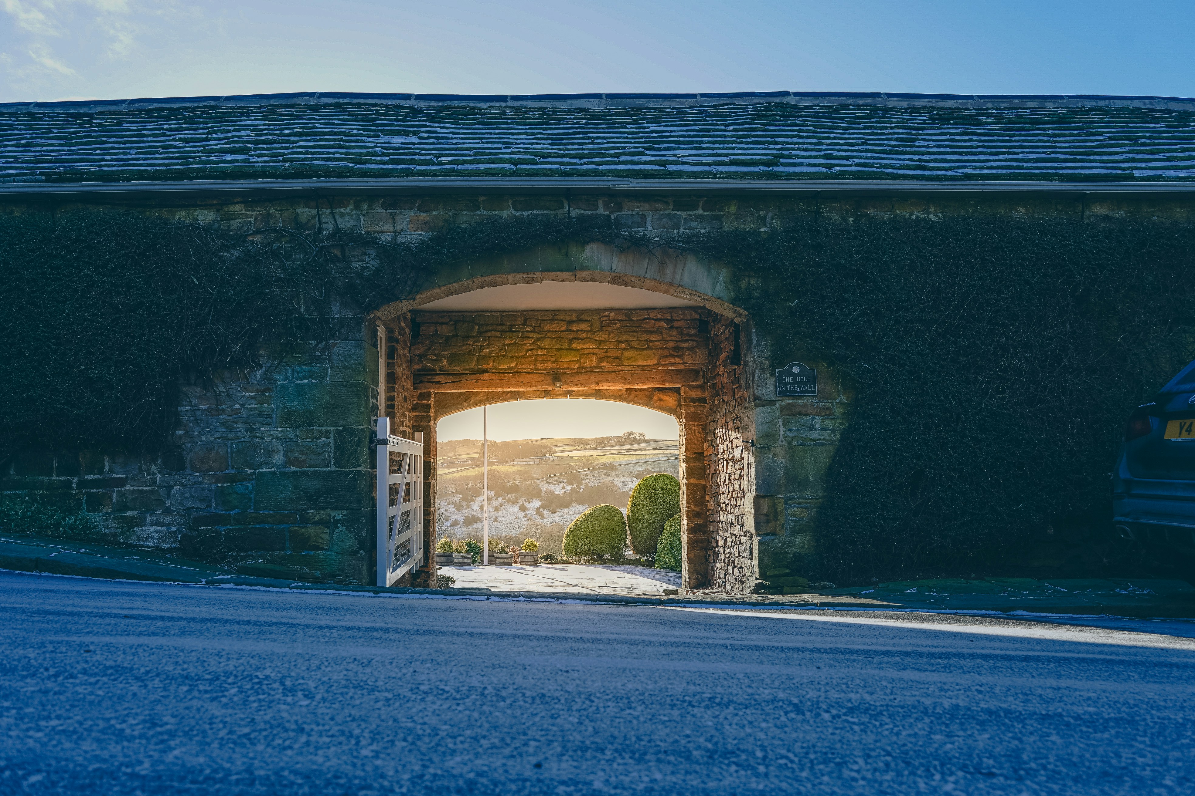 Through the Arch: a Sunlit Valley Unfolds Beyond a Stone Wall