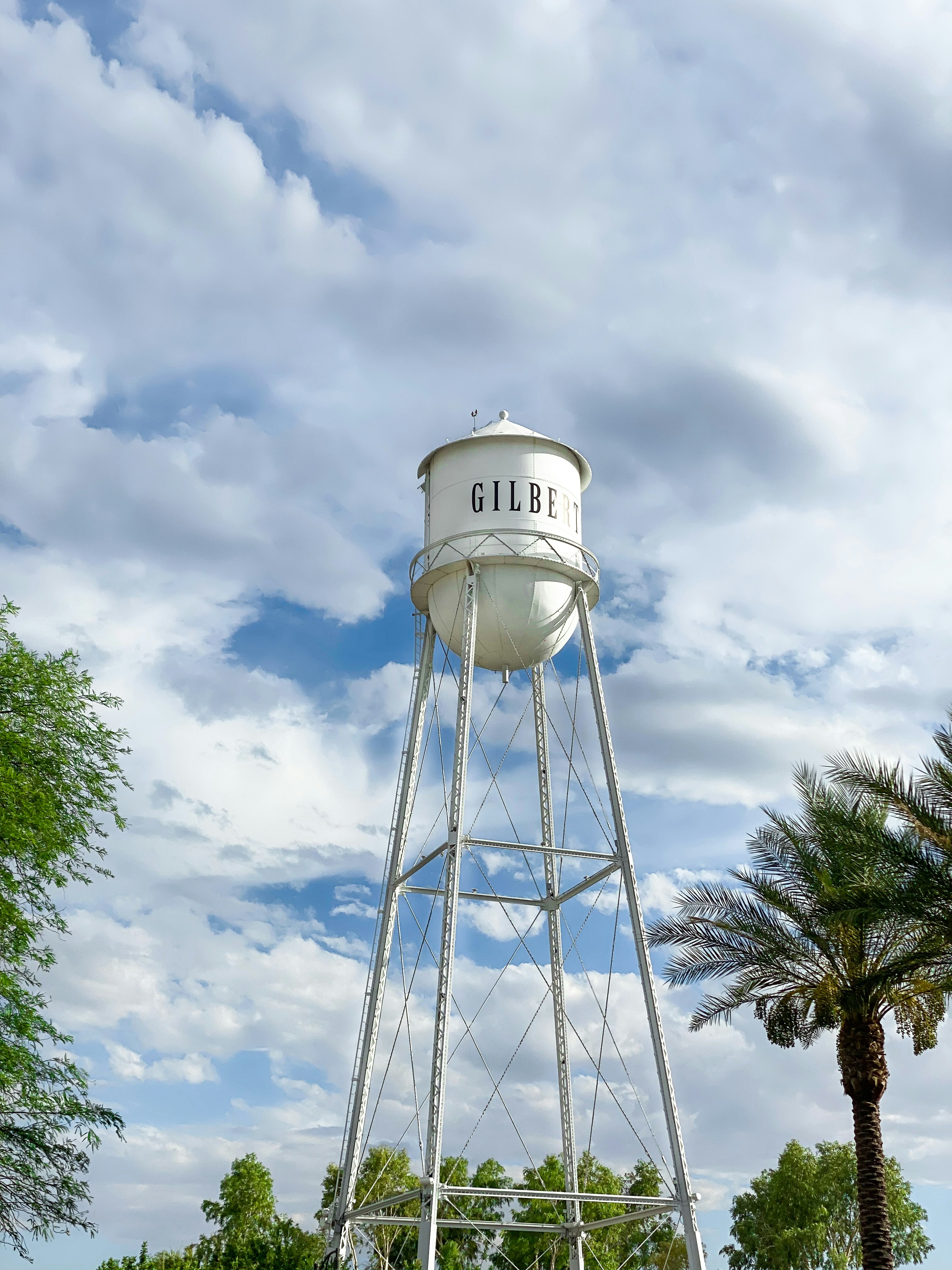 A tall white water tower sitting next to a palm tree photo – Free Water ...