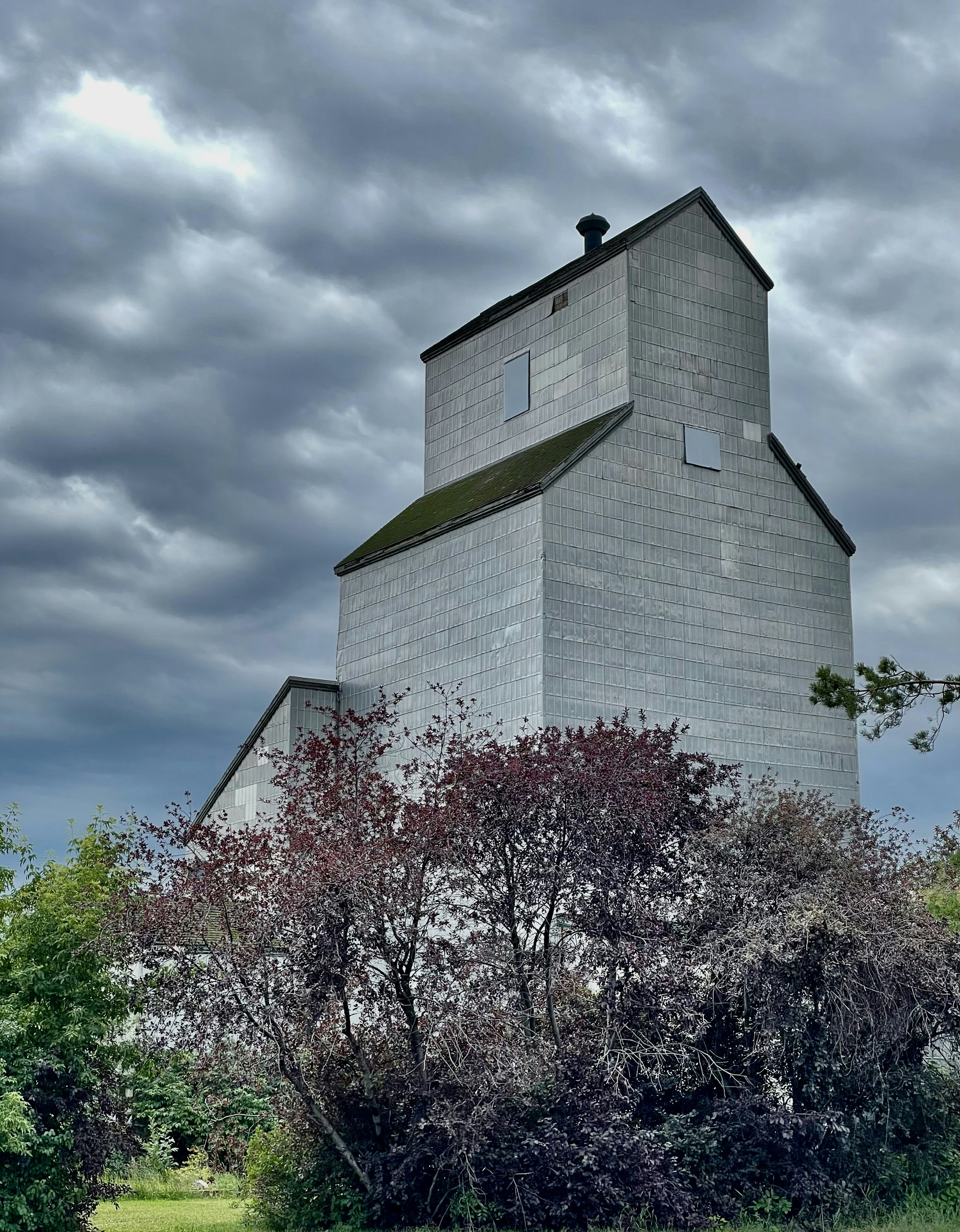 Weathered Grain Elevator Thrusts Upward Beneath Brooding Clouds