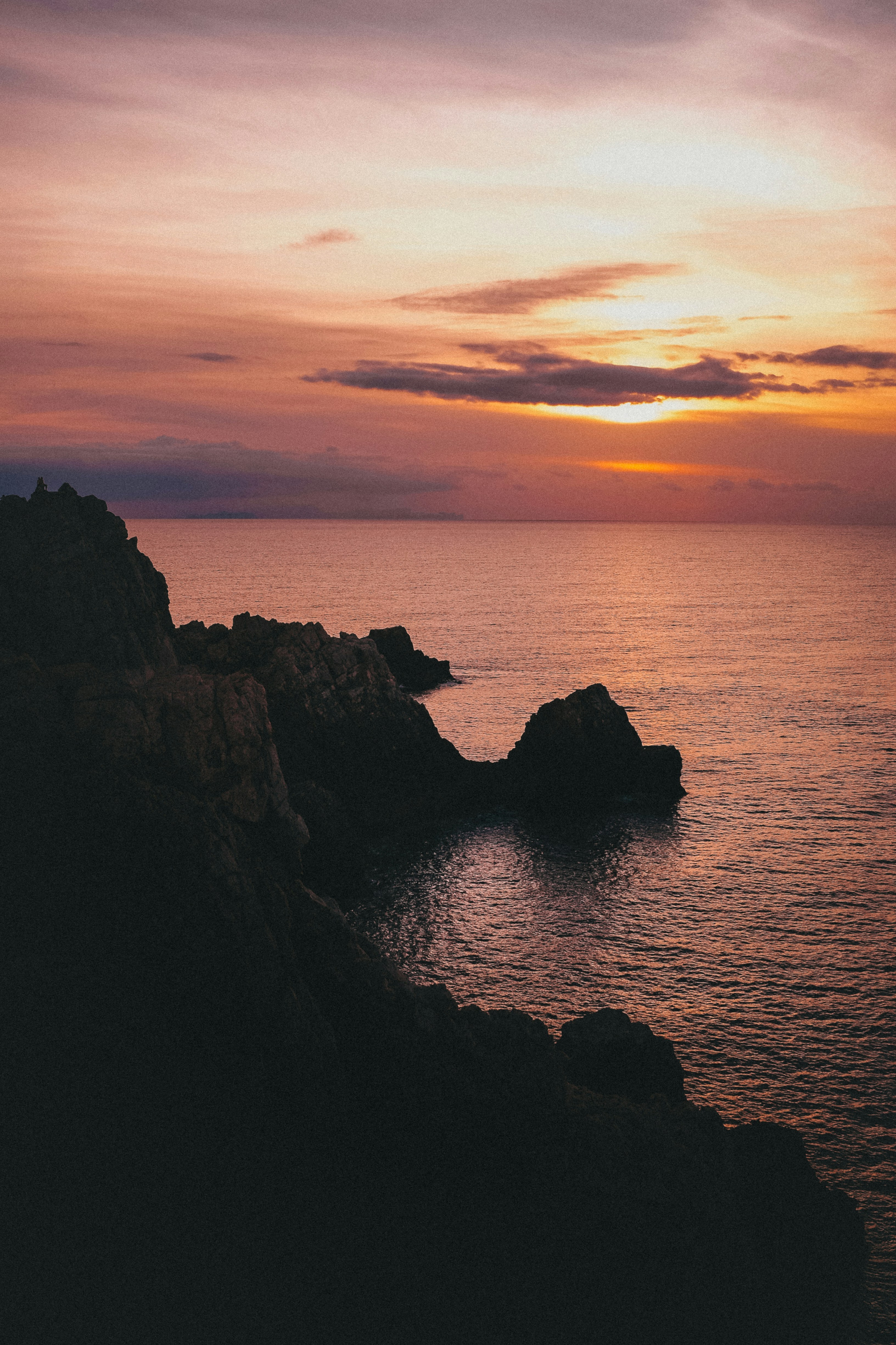 The sun is setting over the ocean and rocks photo – Free Menorca Image ...