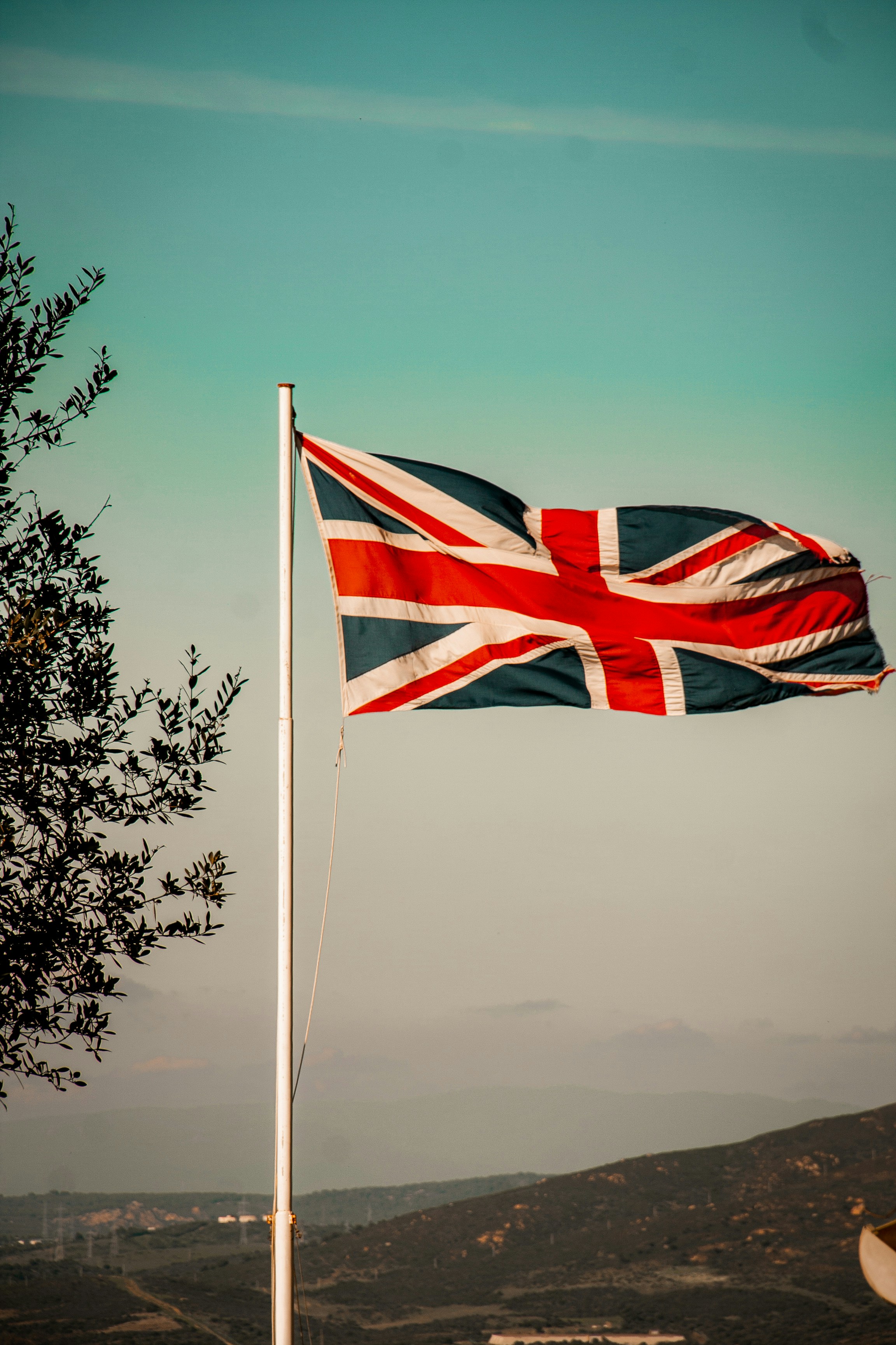Flag in wind over hillside: Union Jack against a teal sky