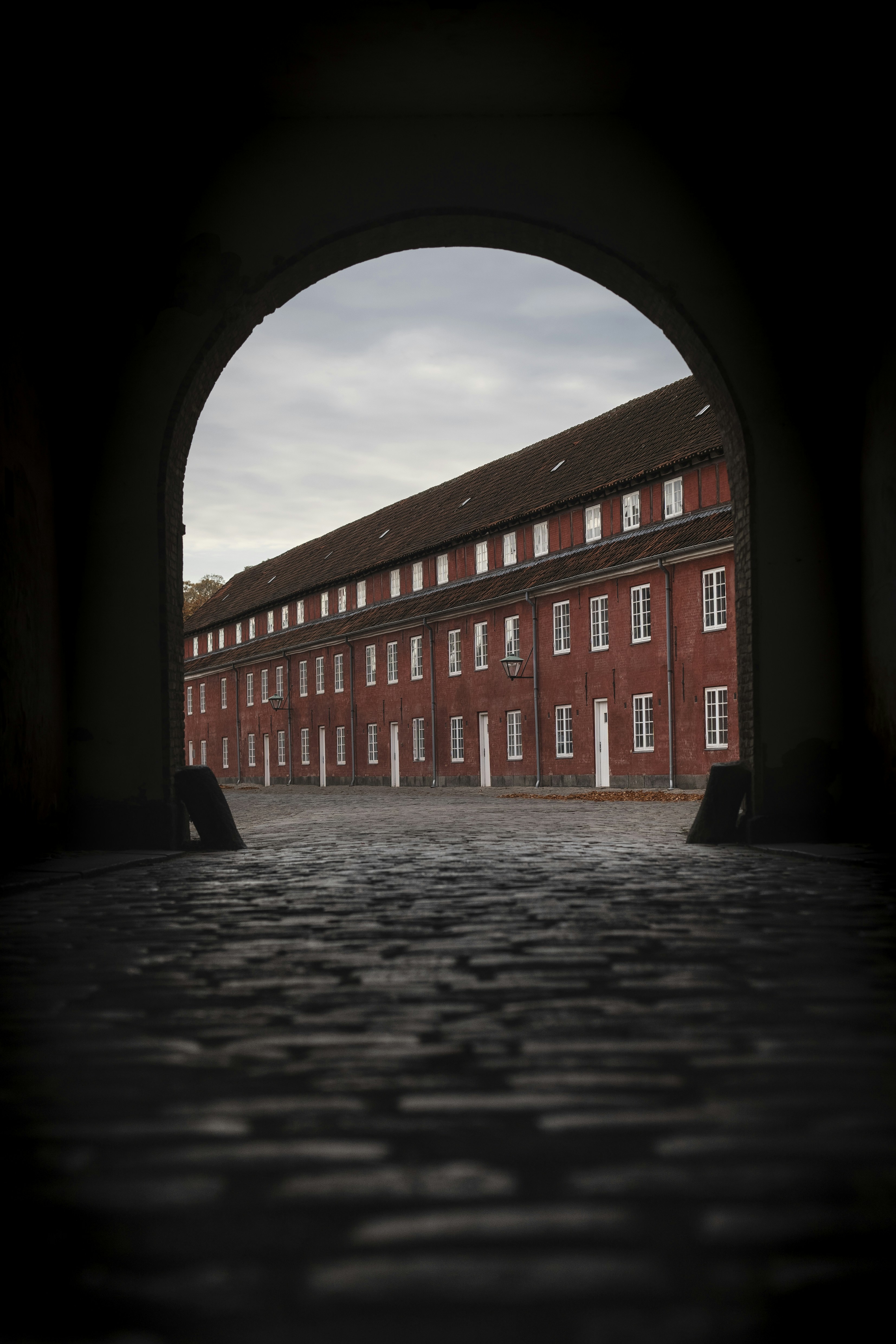 Through the Arch: Red-Brick Corridor Framed by Shadow