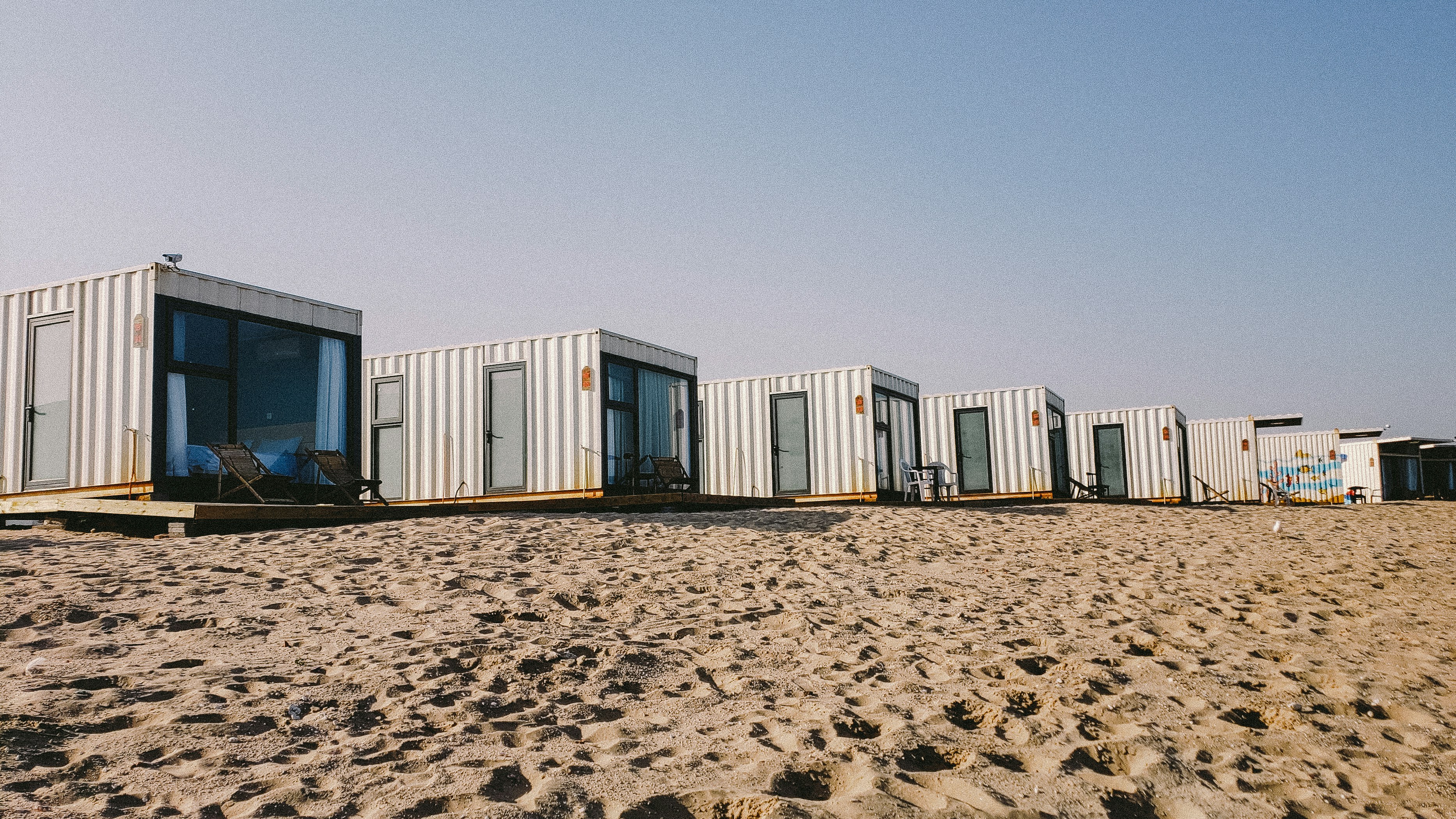 A row of shipping containers sitting on top of a sandy beach photo ...