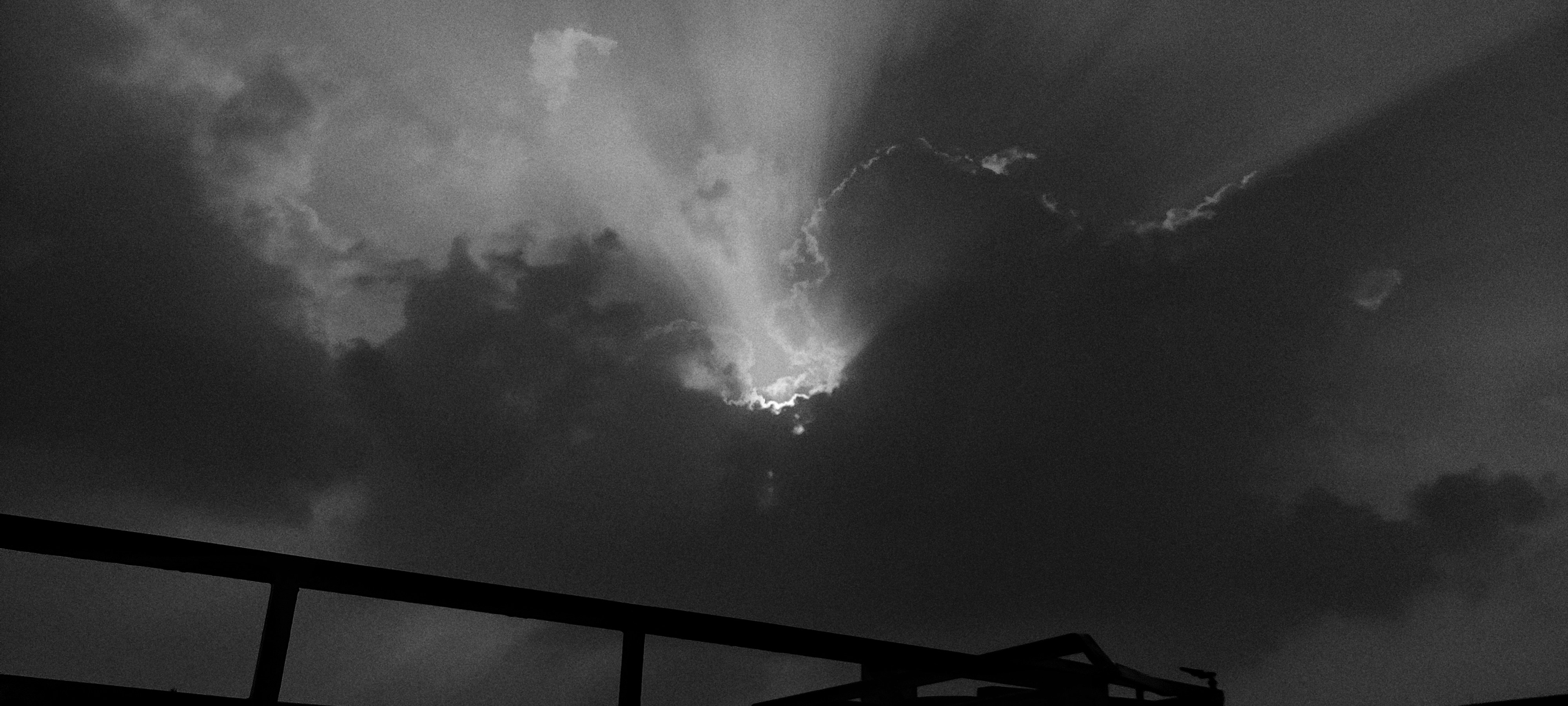 a black and white photo of the sun shining through the clouds