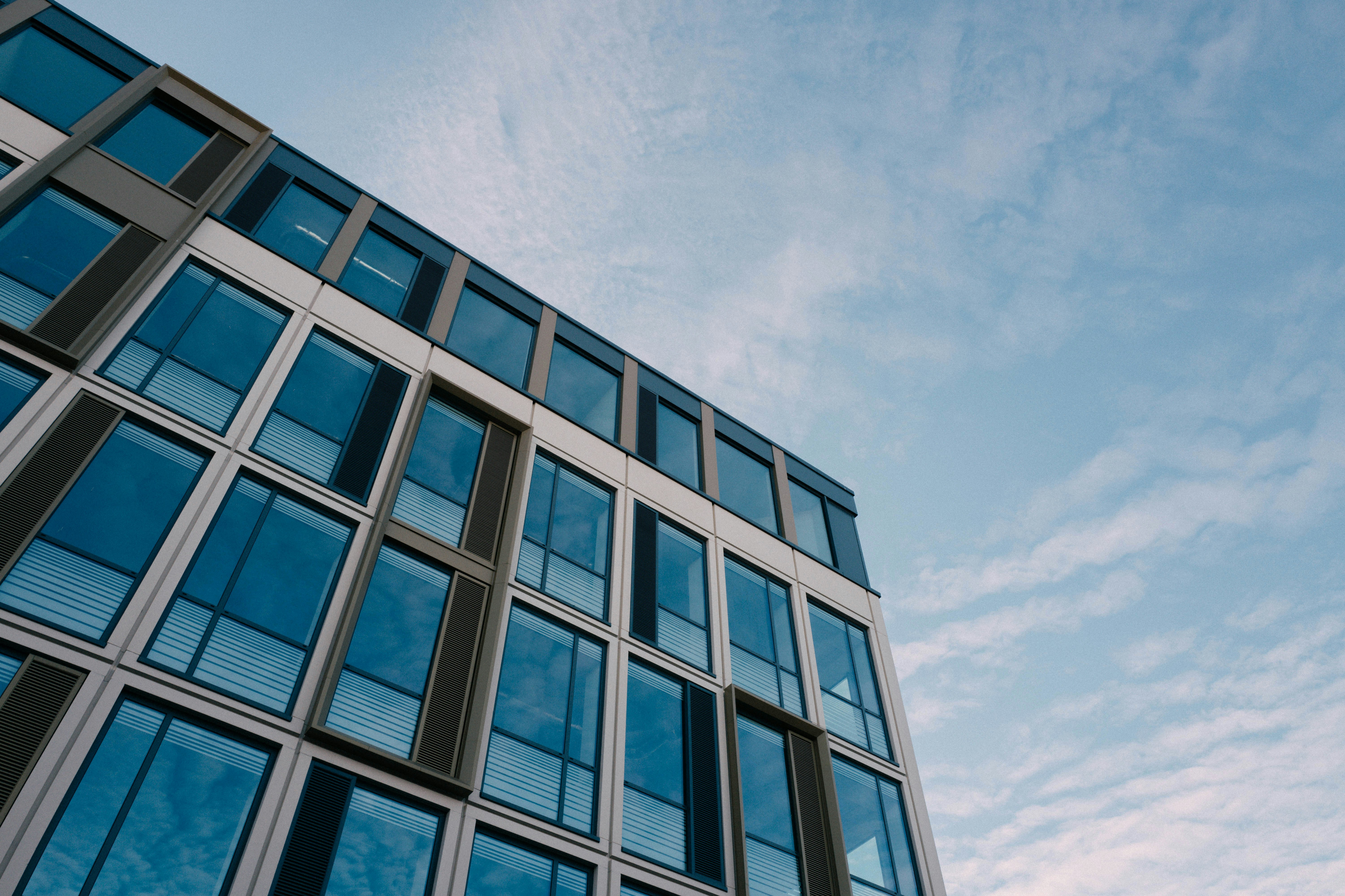 Modern glass building reflecting the sky with scattered clouds.