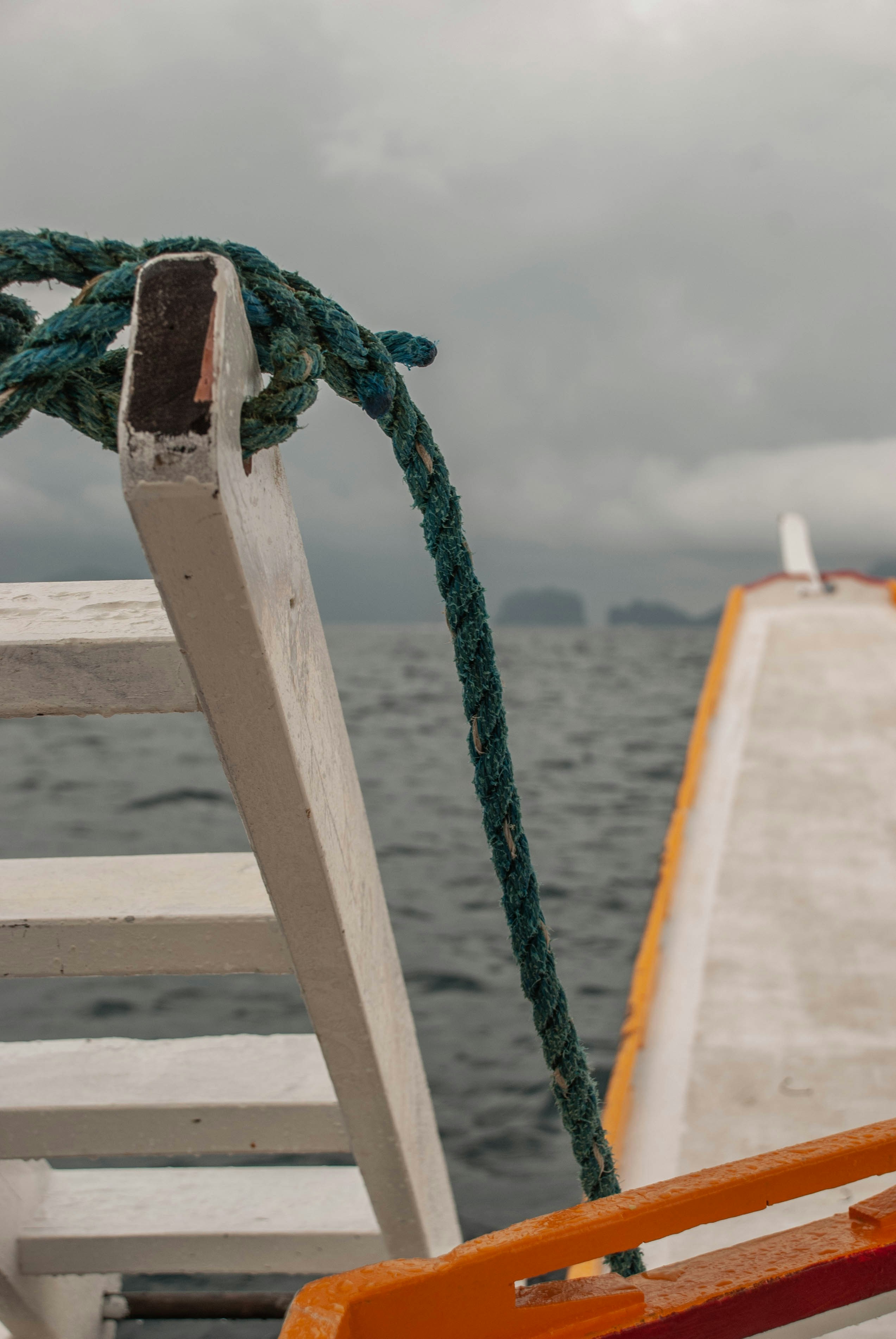 Arc of Teal Rope Over a Weathered Bow Toward a Misty Horizon