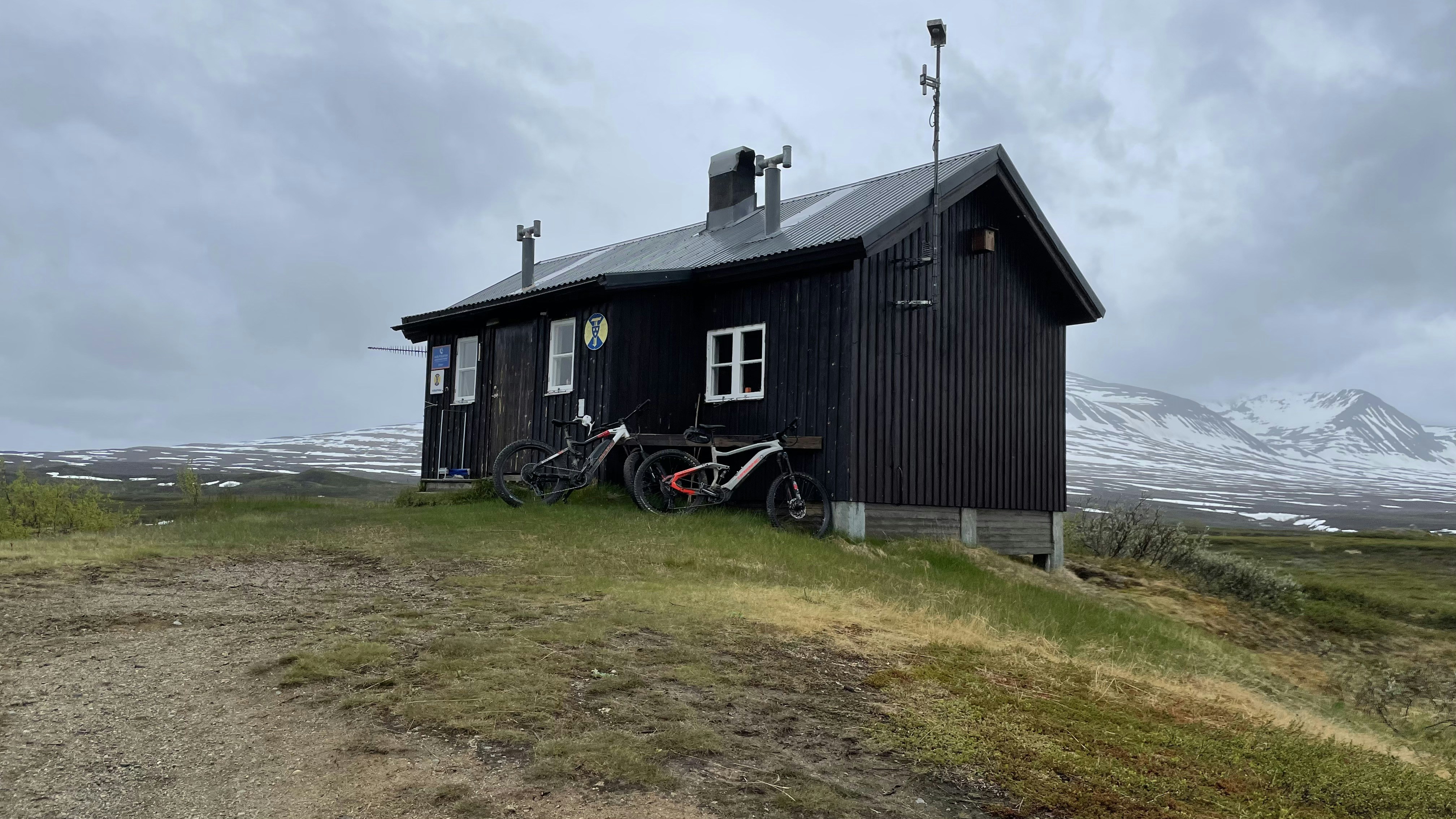 Dark-Wood Cabin on a Wind-Swept Plateau Framed by Snowy Peaks