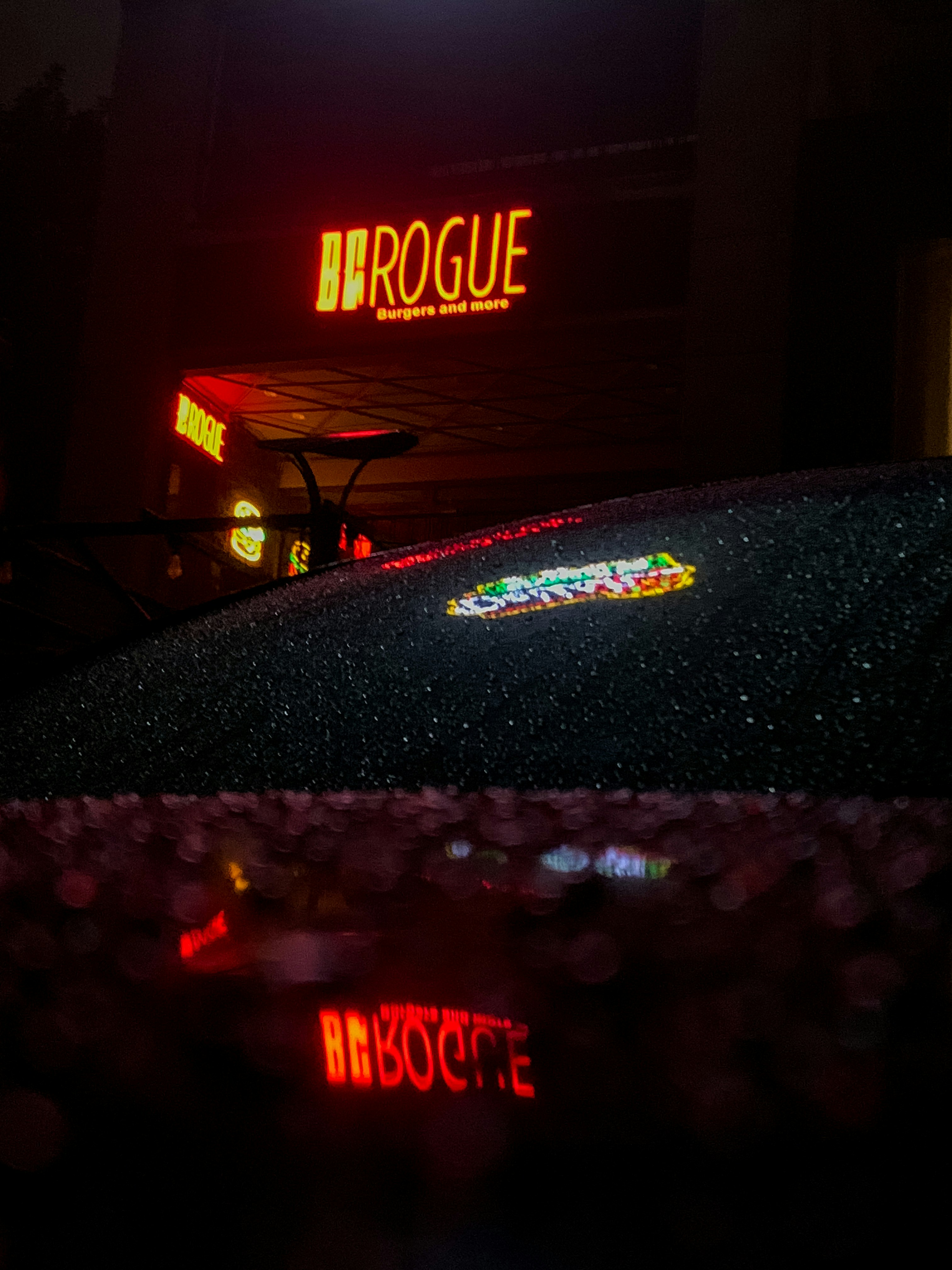 Neon Burger Reflections on a Rain-Dusted Hood