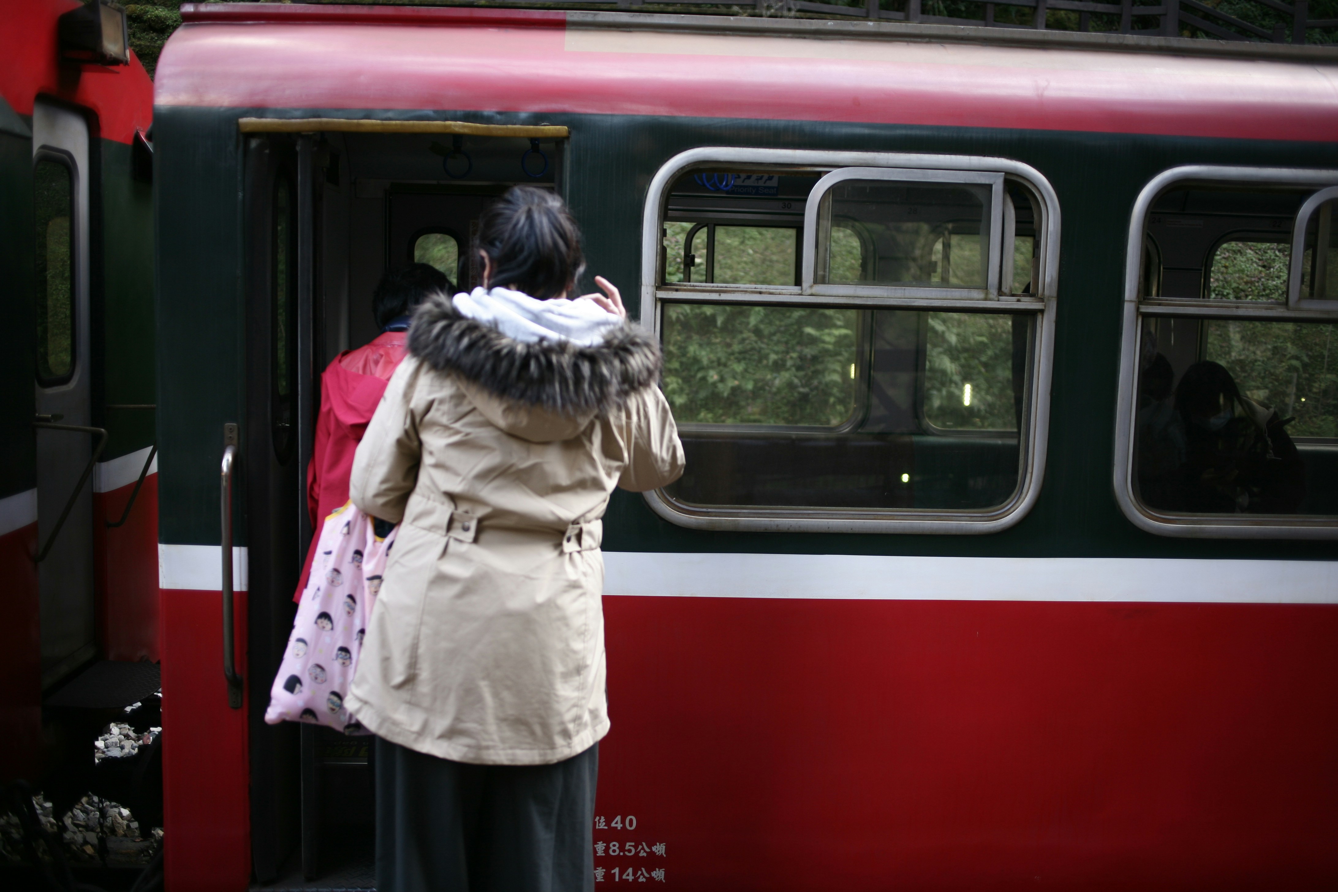 a woman standing on the side of a red and green train