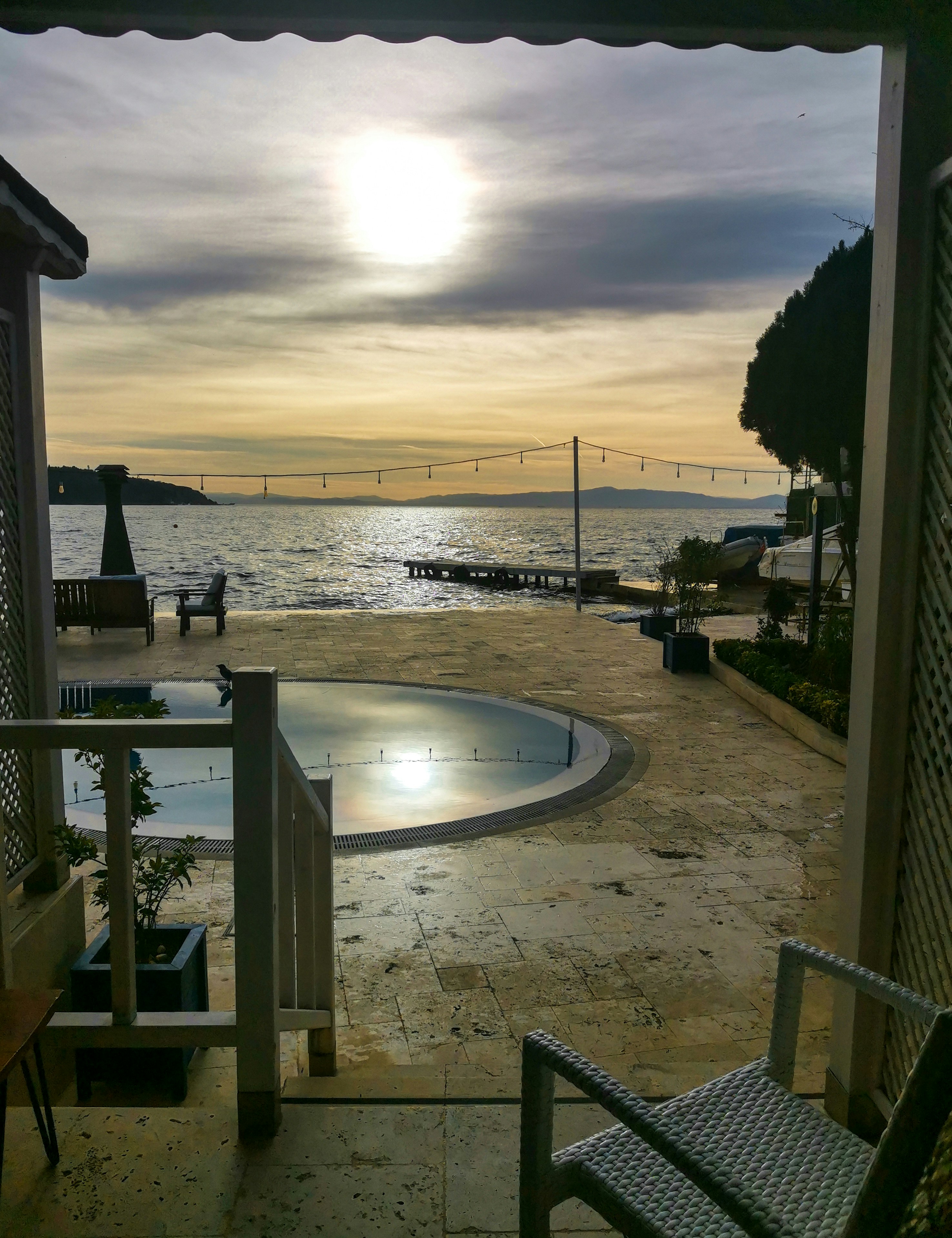 Sunlit harbor framed by a terrace doorway at golden hour