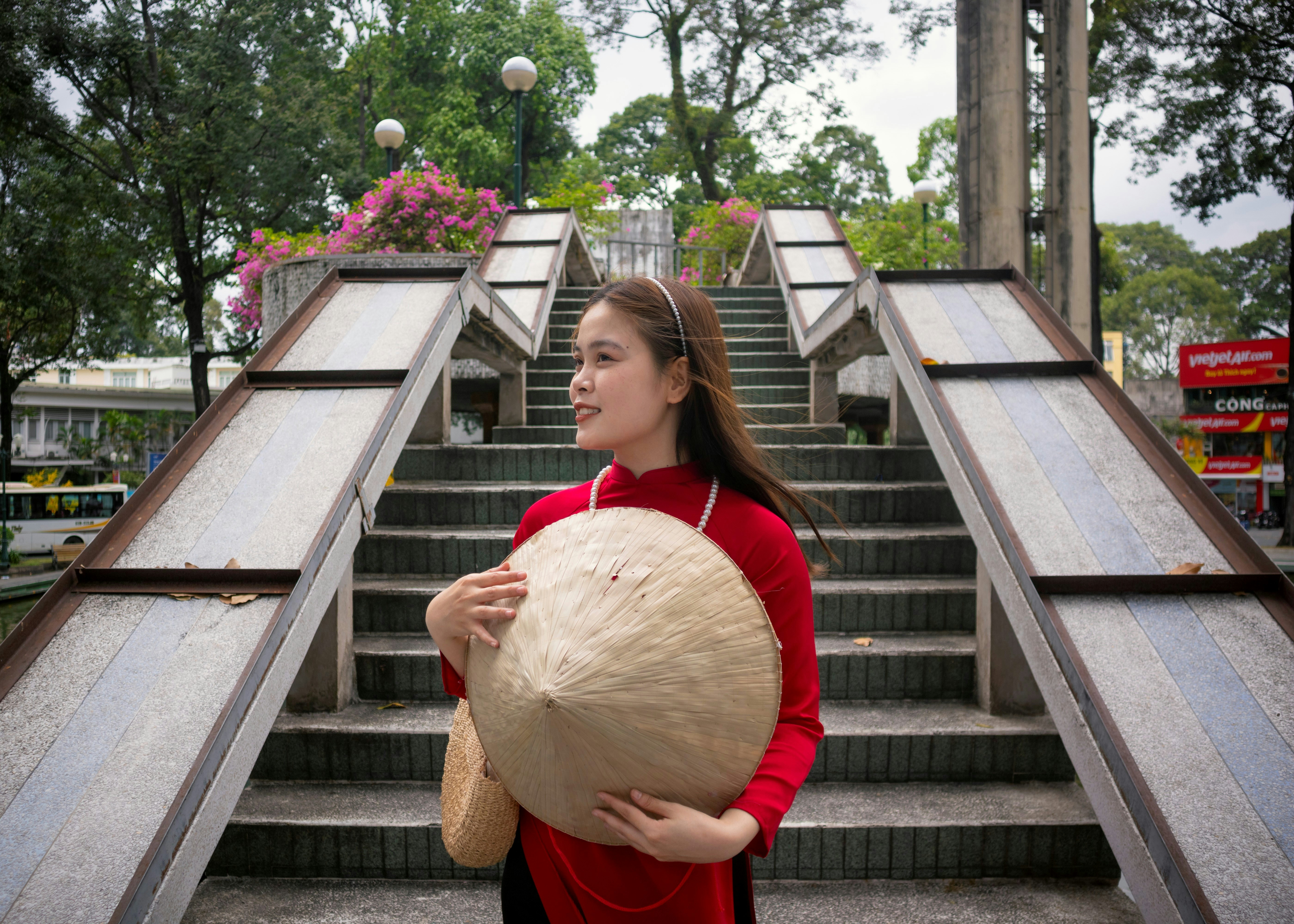 a woman holding a large hat while standing in front of a set of stairs