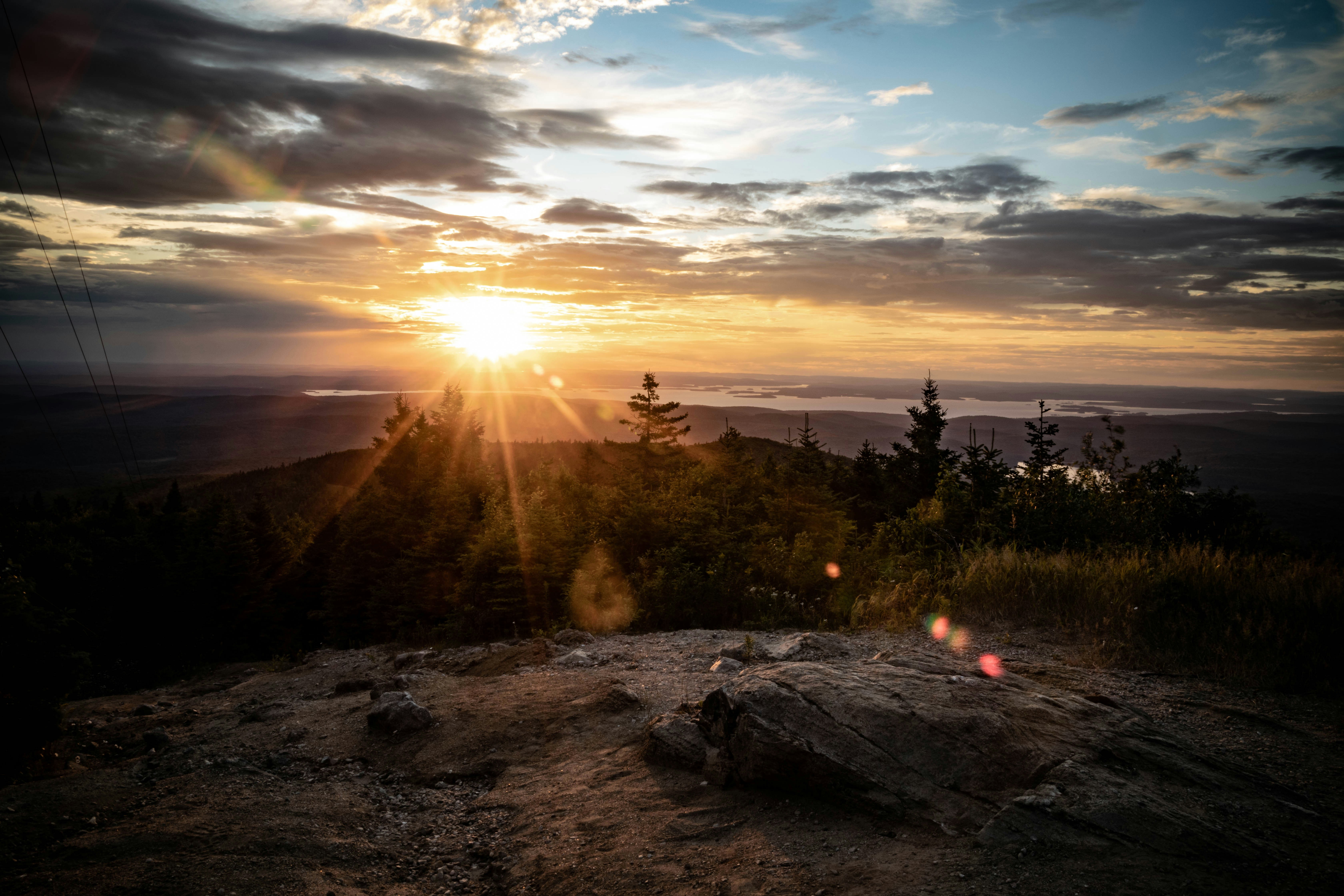 Sunrise casting warm hues over a rocky summit with scattered clouds.