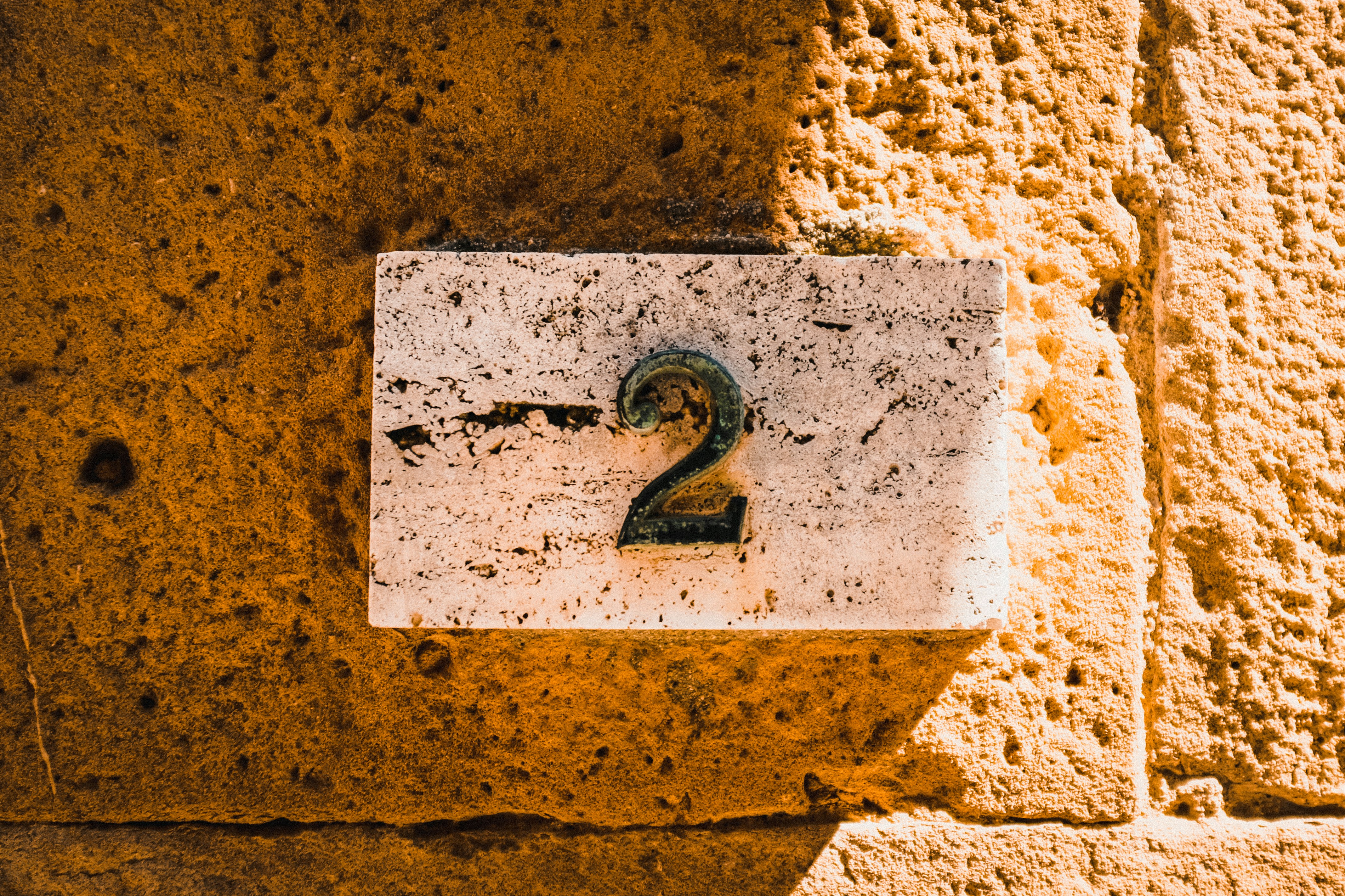 A number two sign on a stone wall photo – Free Number Image on Unsplash
