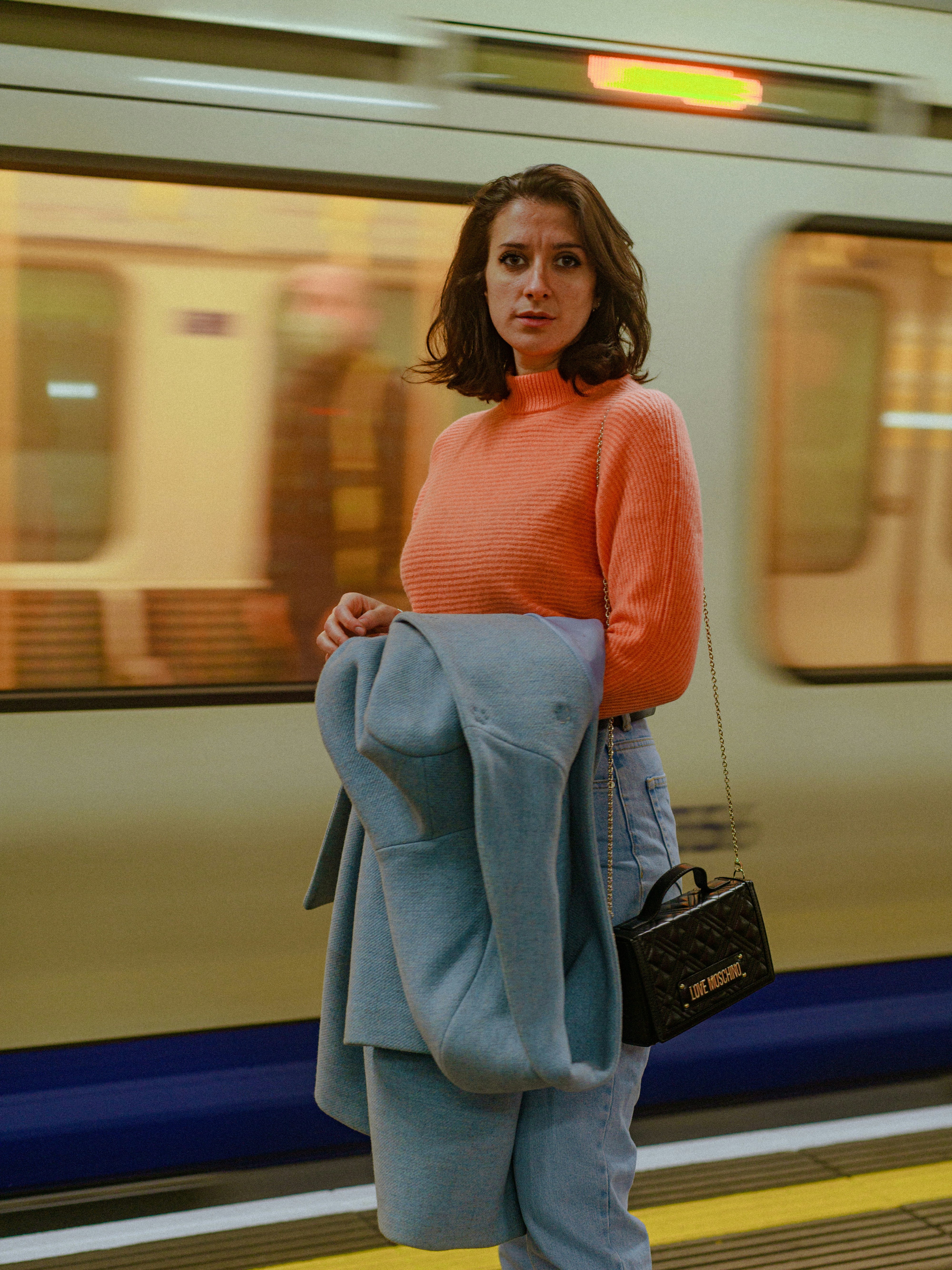Transit Moments: A Woman in a Coral Sweater Waits on the Platform