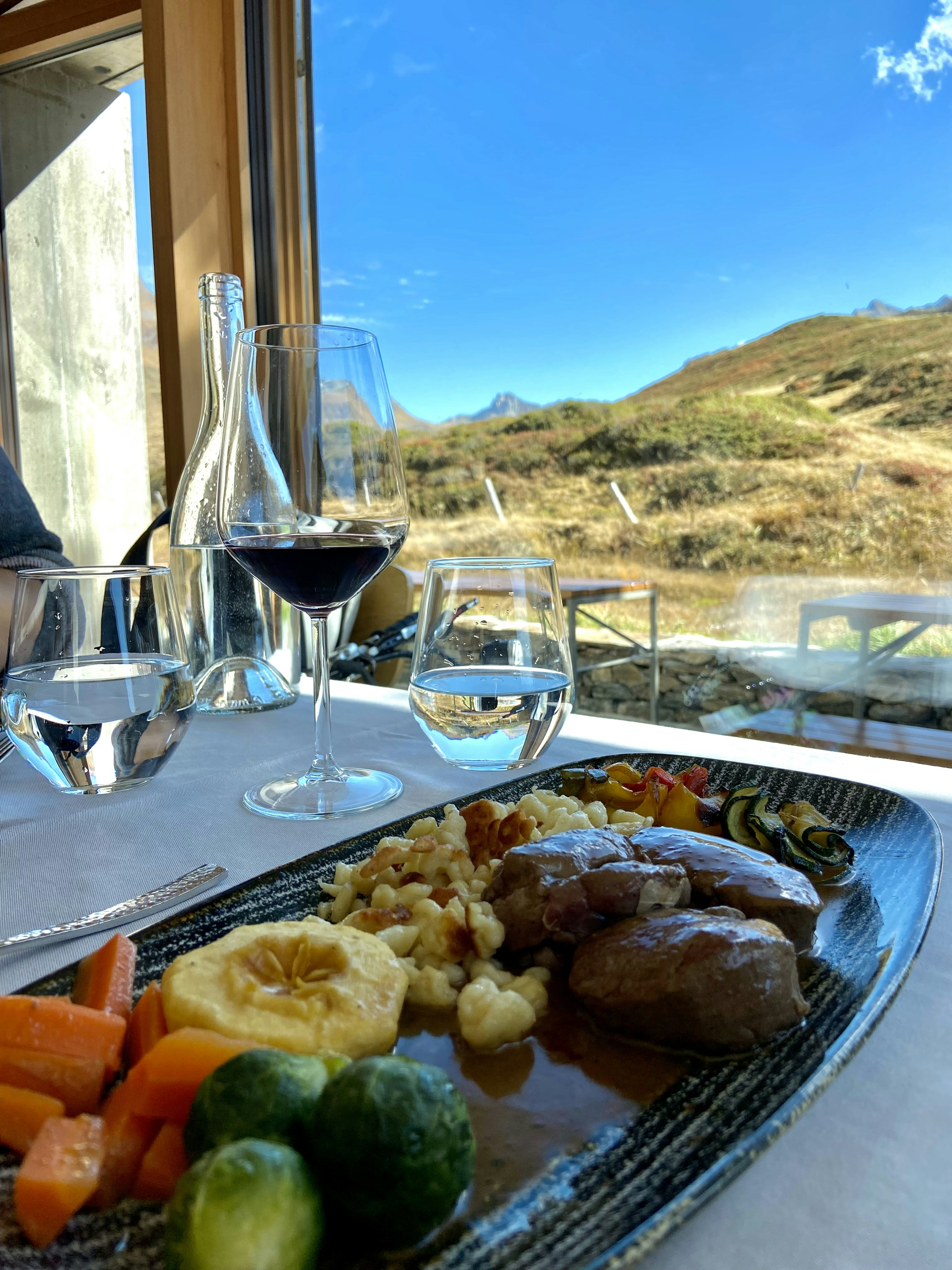 Alpine Window Dinner: Plates, Glasses, and a Sunlit Vista