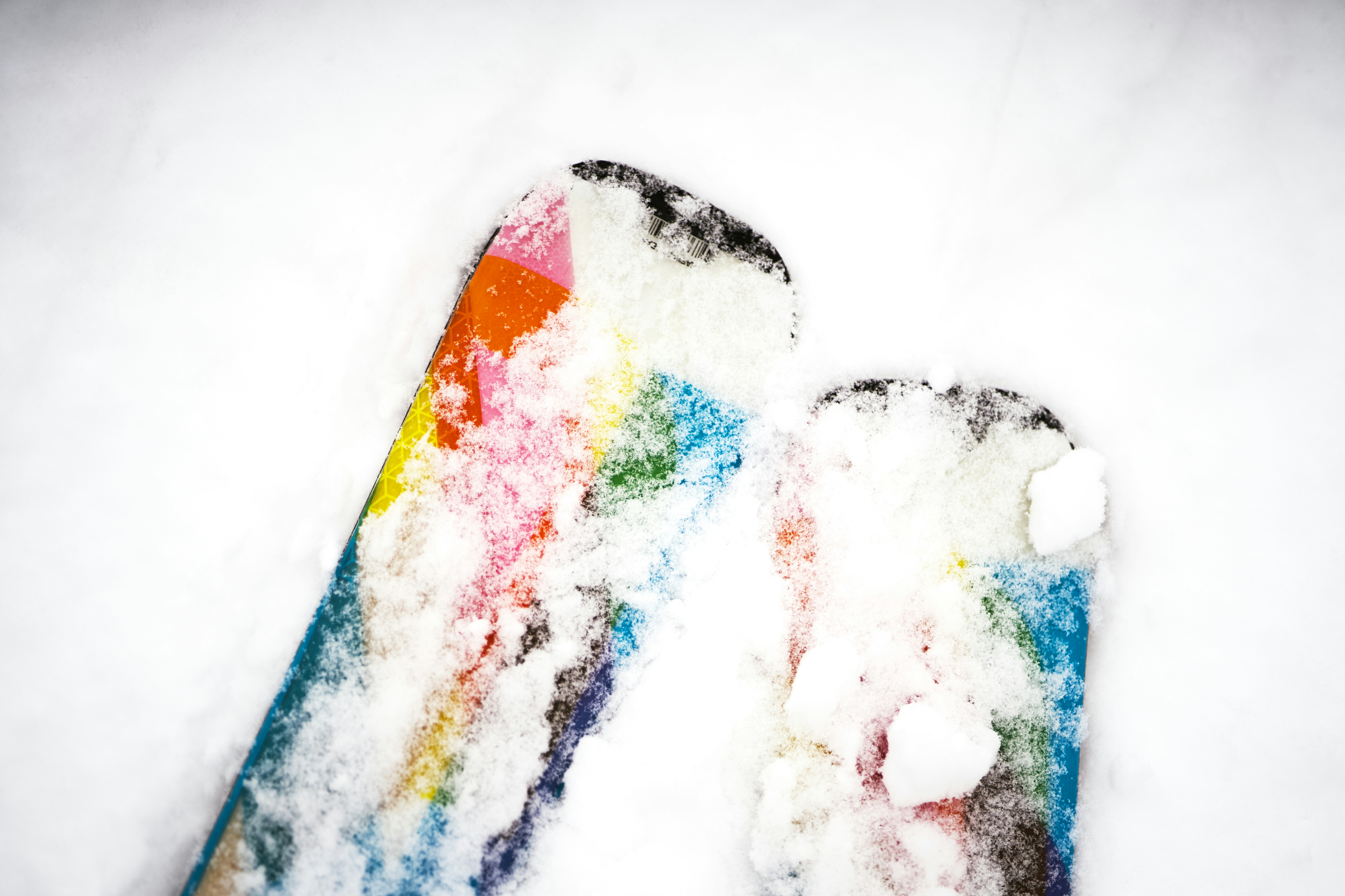 Color Burst in White: Rainbow Skis Nestled in Fresh Snow