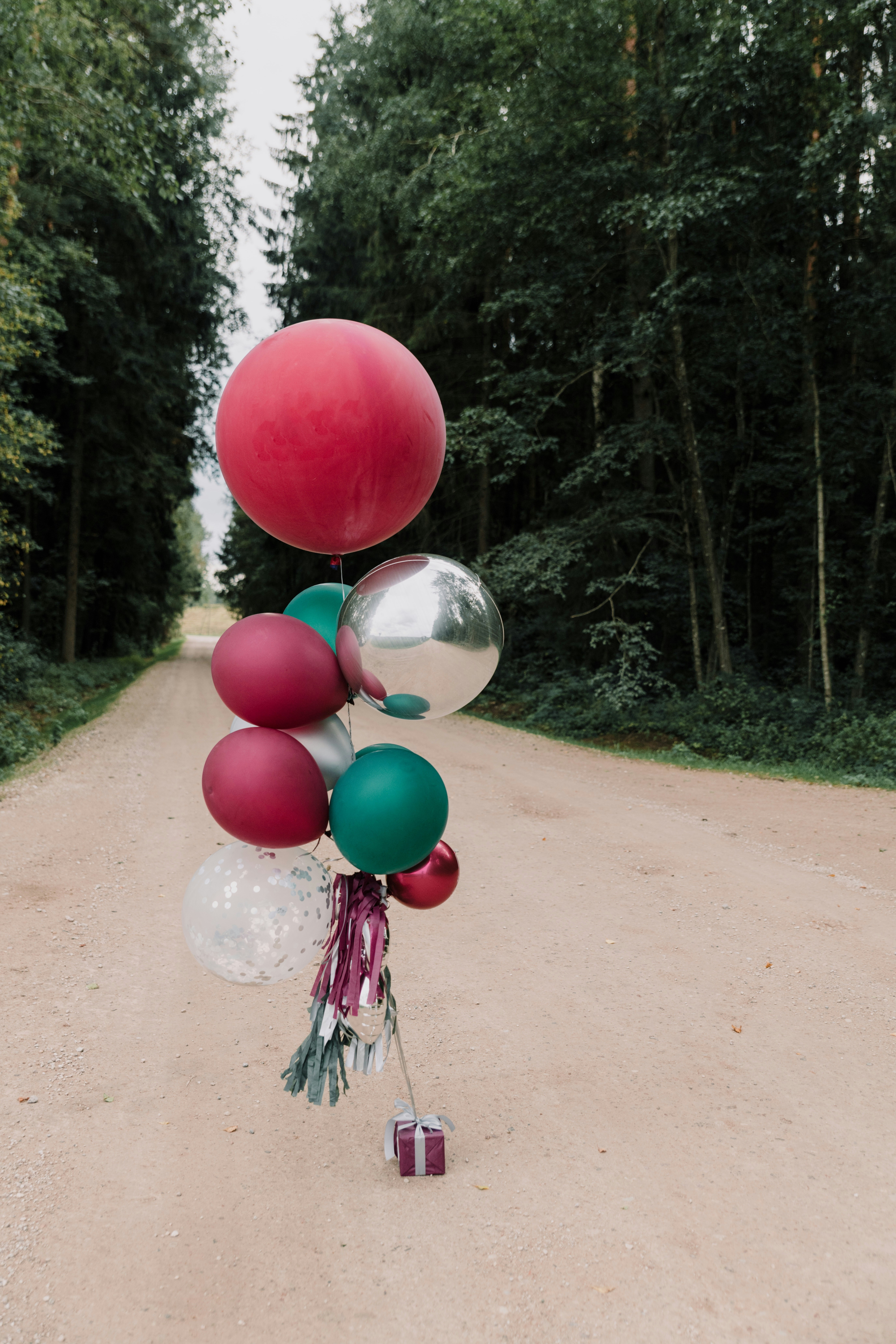 A bunch of balloons on the side of a dirt road photo – Free Balloon ...