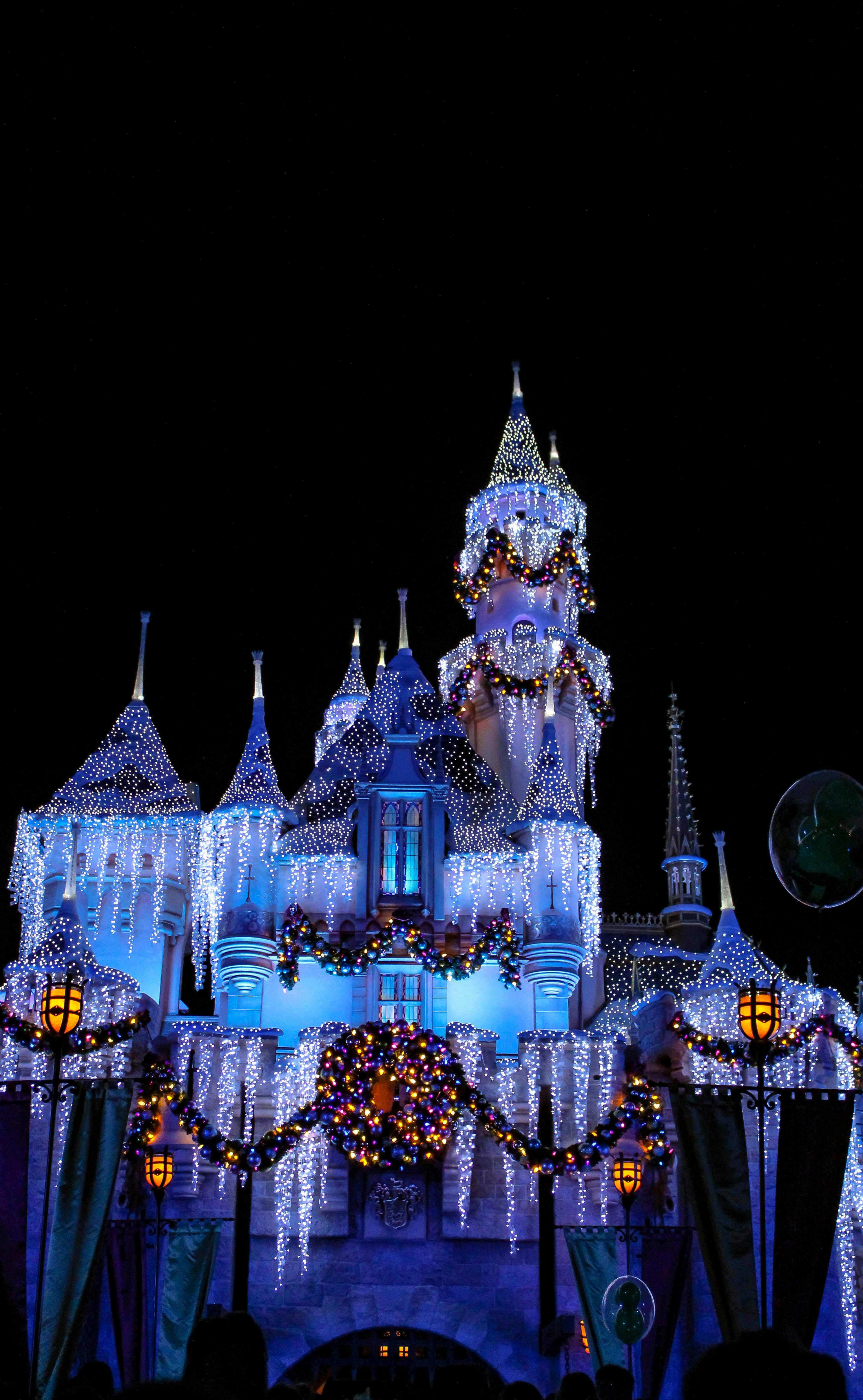 A majestic castle adorned with sparkling lights and festive decorations, capturing the magic of the holiday season at night.